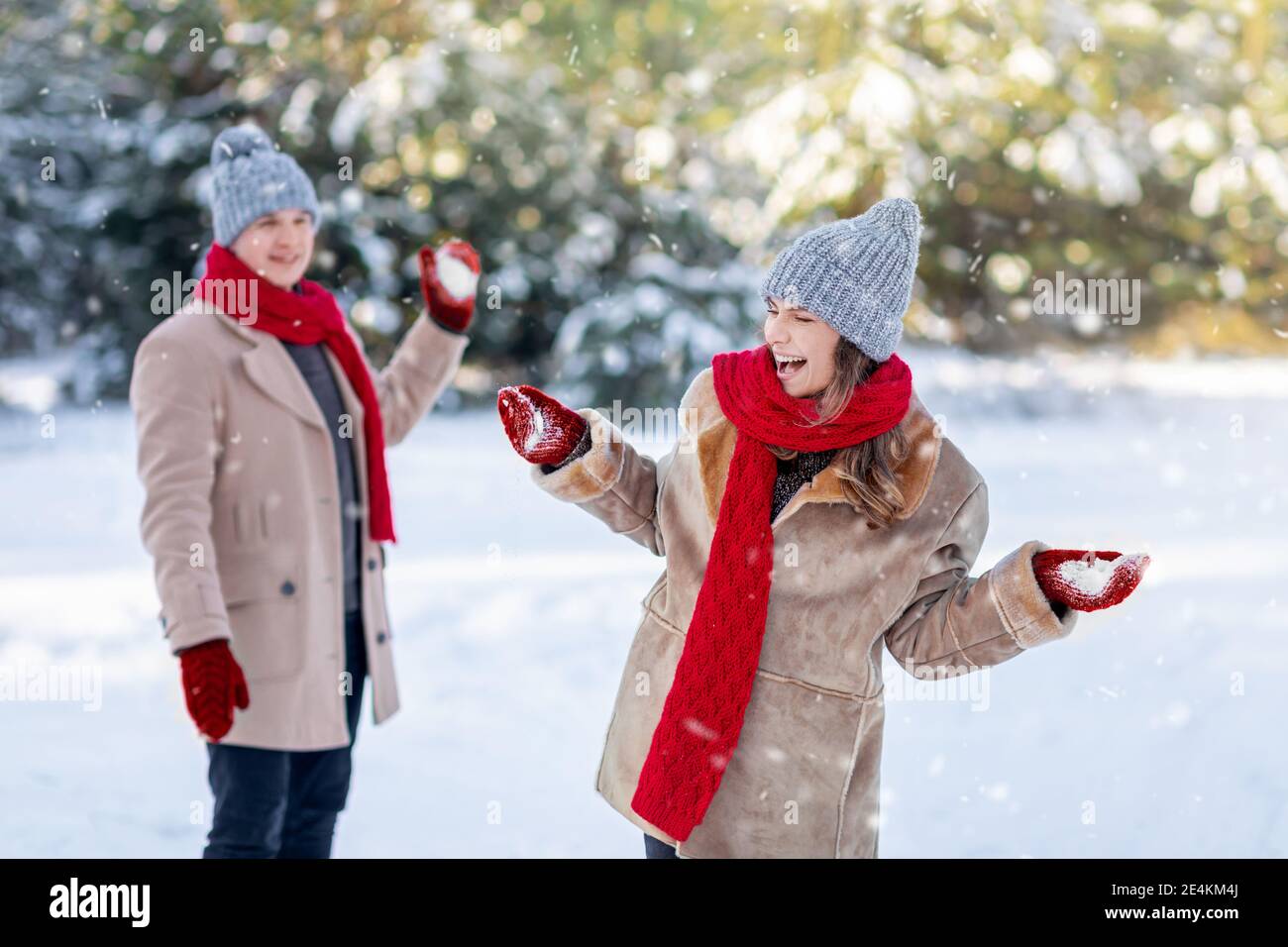 Emotional man and woman playing snowballs at city park, copy space ...