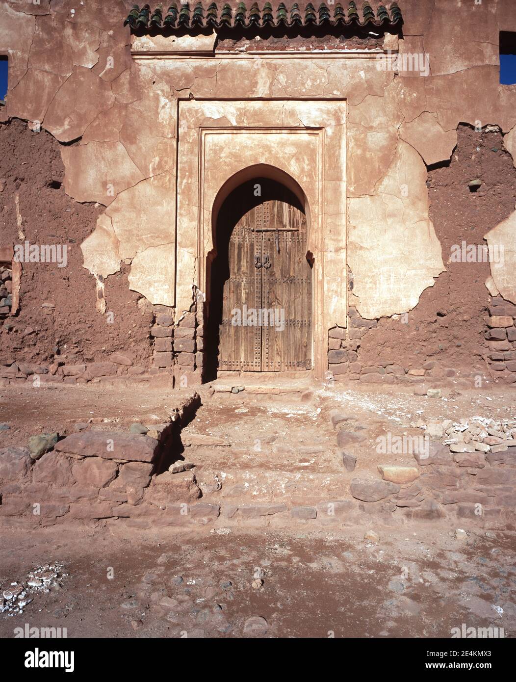 Traditional arched doorway and wooden door set in an old crumbling ...