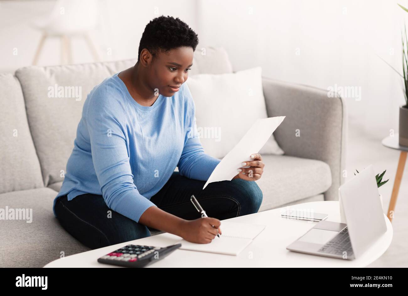 Black woman writing report working on laptop at home Stock Photo - Alamy