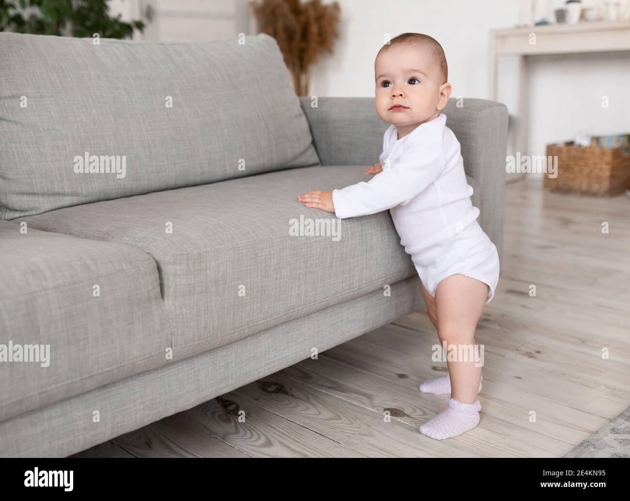 Little Baby Toddler Standing Near Couch Looking Aside At Home Stock ...