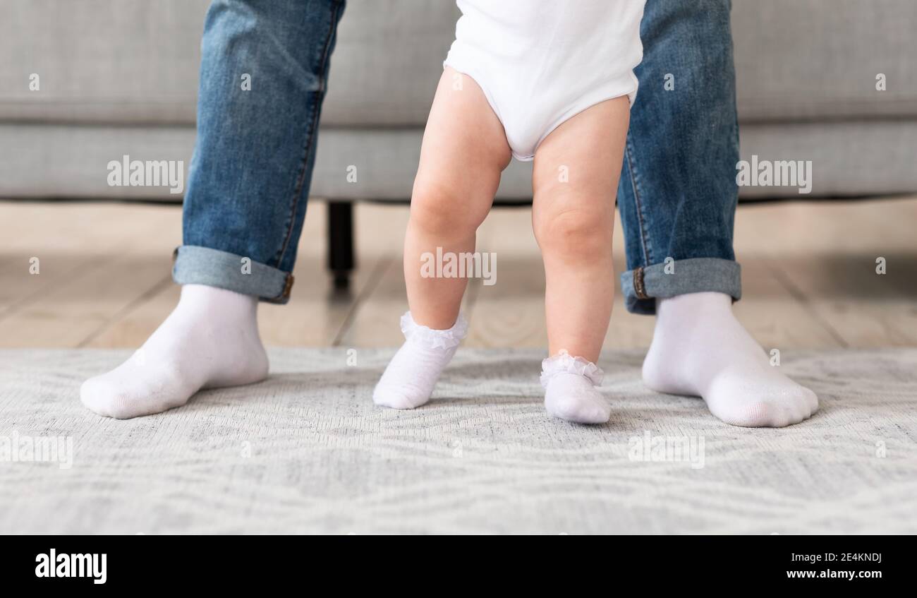 Father Helping Baby Toddler Make First Steps Standing Indoors, Cropped ...