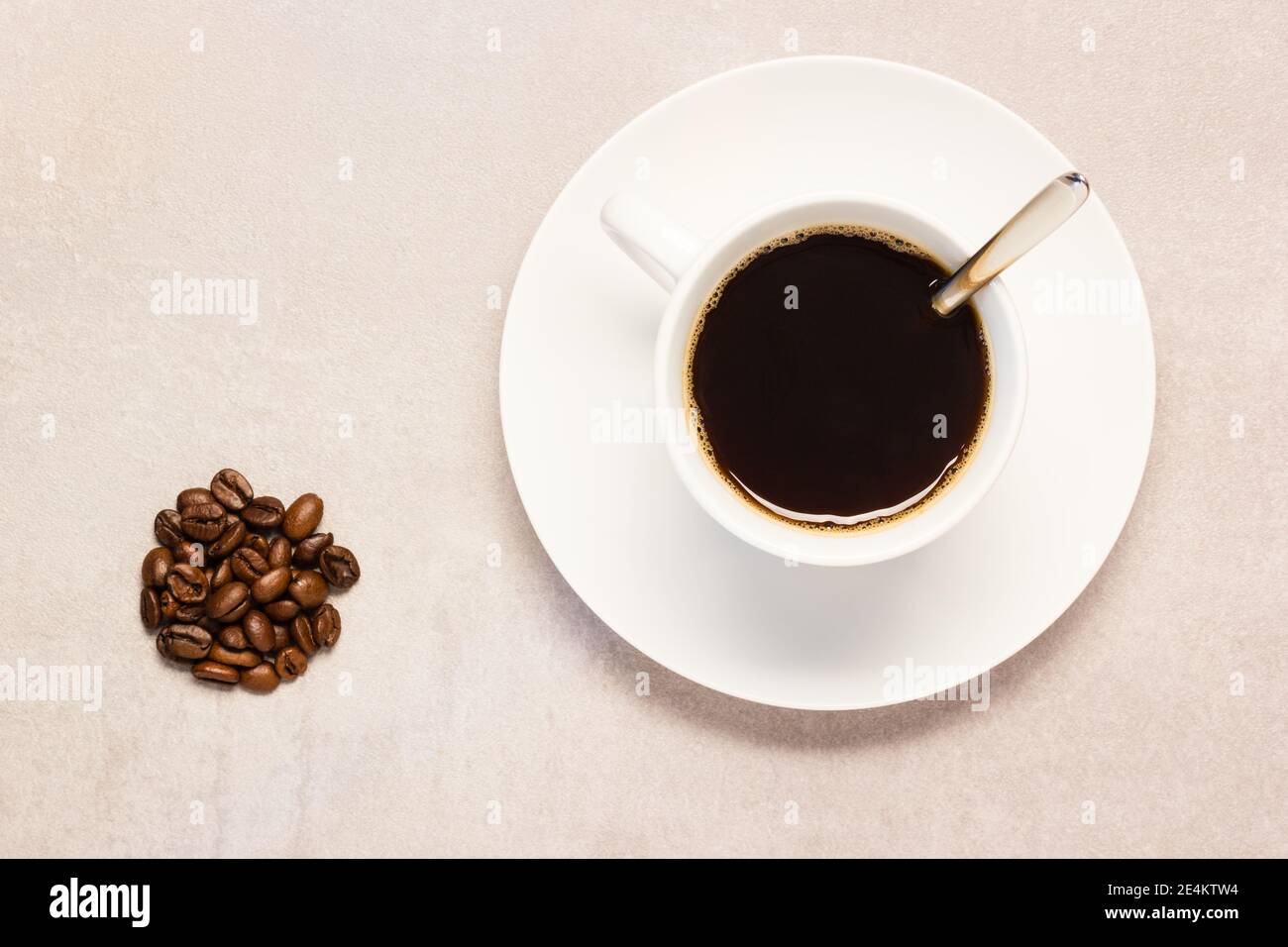 A cup of freshly brewed coffee cup and spoon having some roasted coffee ...