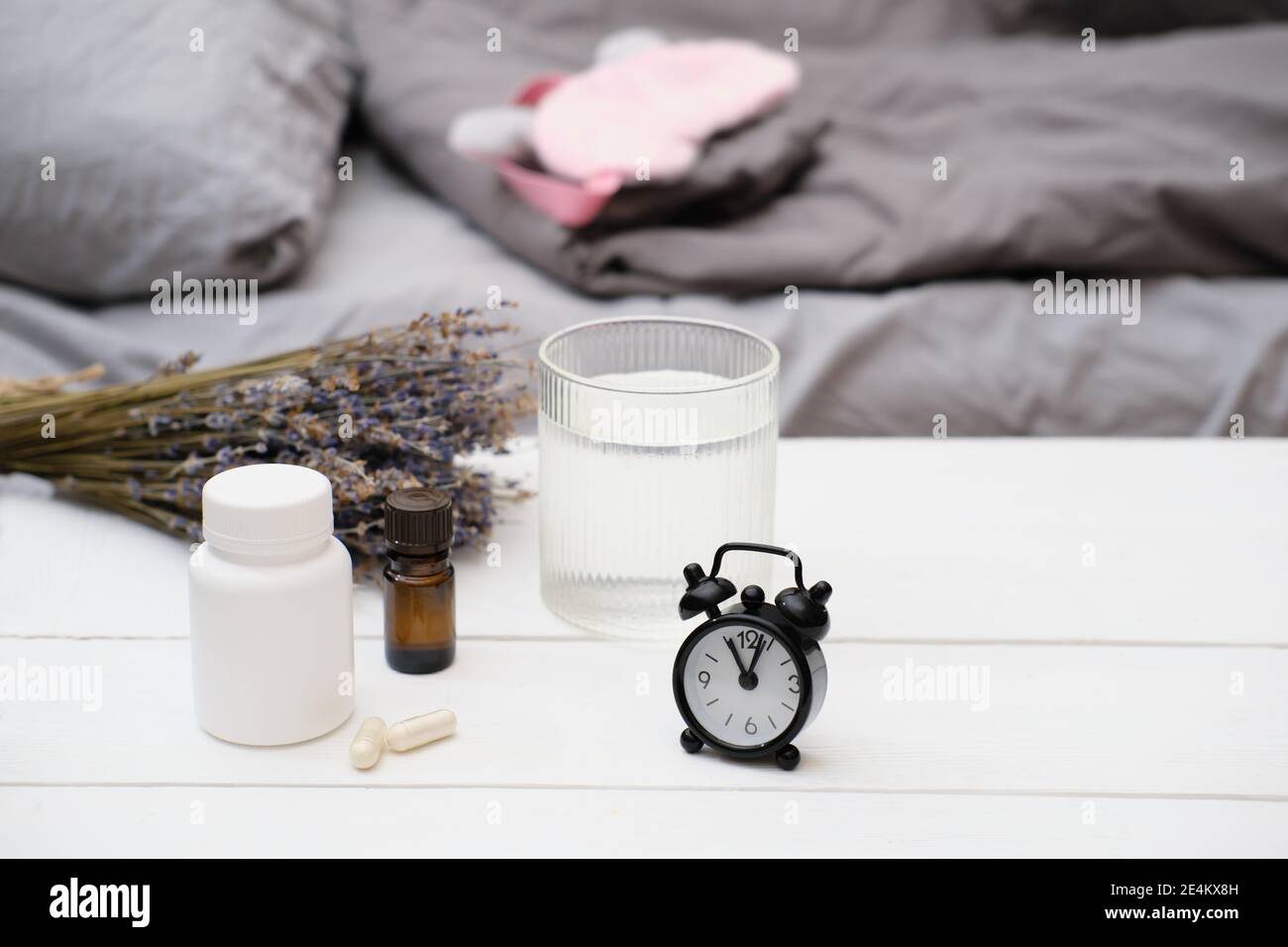 melatonin capsules and lavender essential oil on a bedside table ...