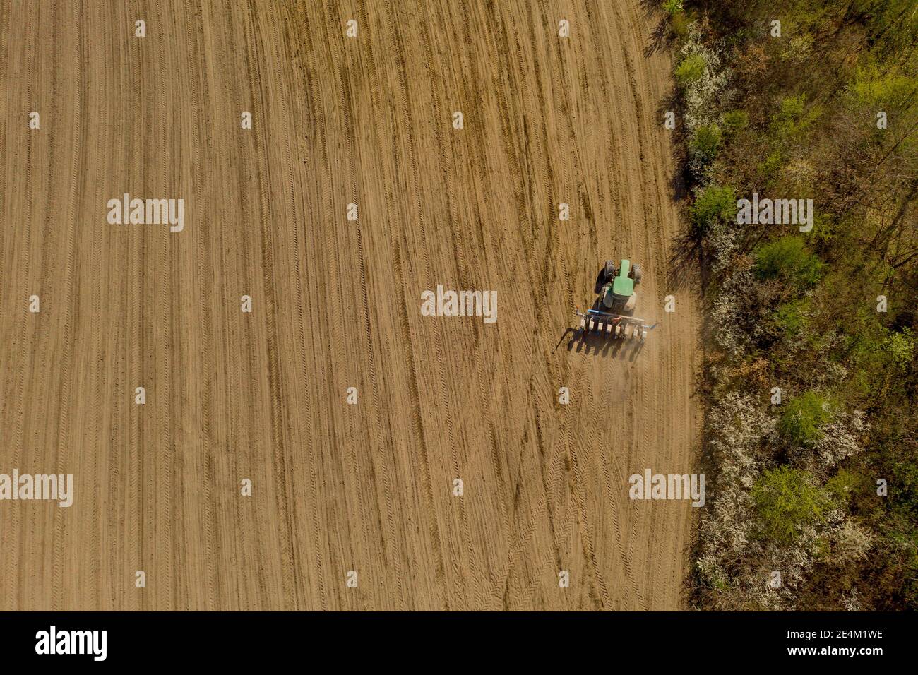 Aerial view large tractor cultivating a dry field. Top down aerial view ...