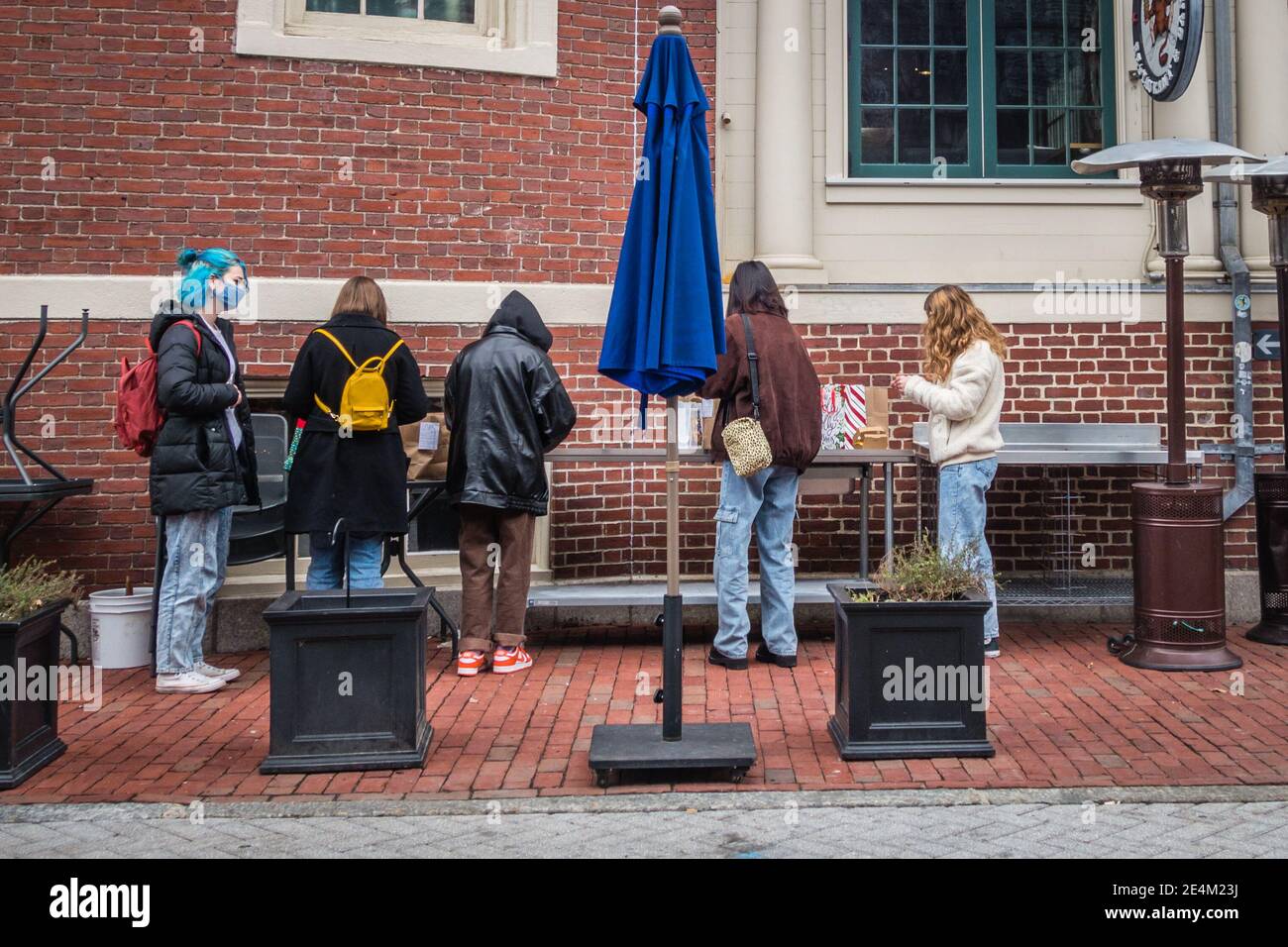 People line up for curbside pickup outside of restaurant where bags of ...