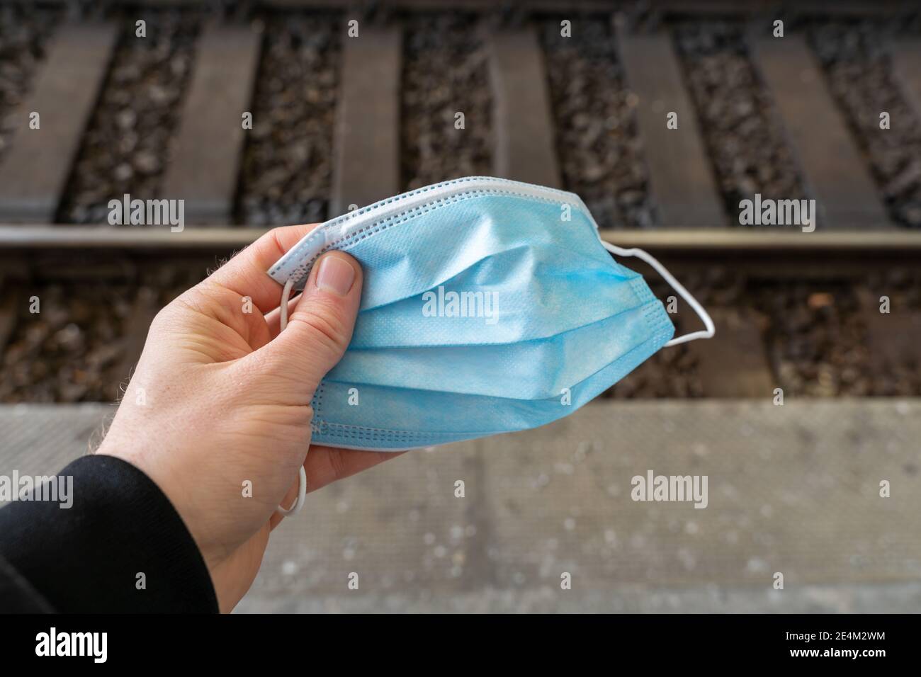 Medical blue face mask on a train platform with rails and a track bed ...
