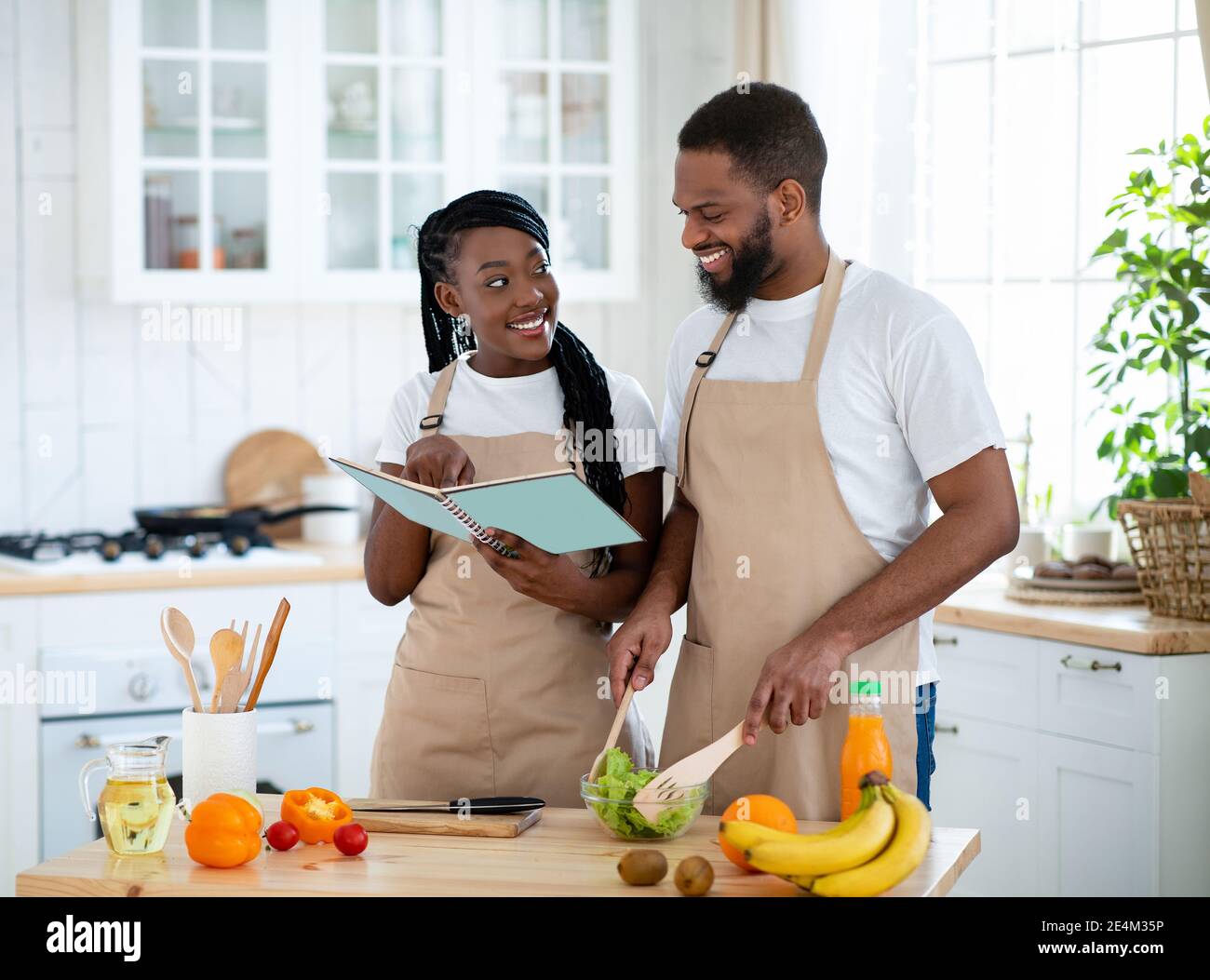 Happy Black Couple Checking Recipe In Cookbook While Cooking Together ...