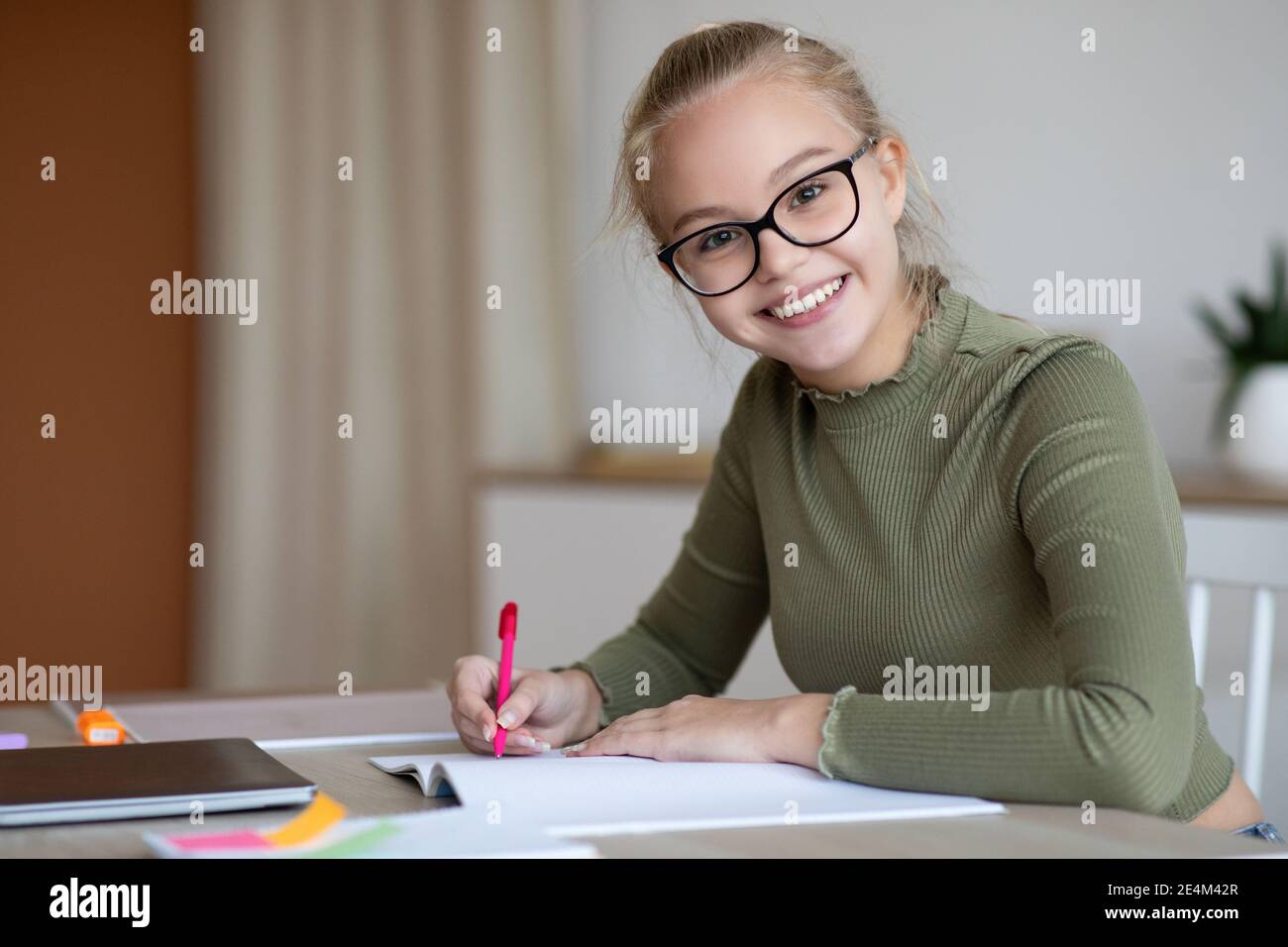 Pretty school girl writing in notepad and smiling Stock Photo - Alamy