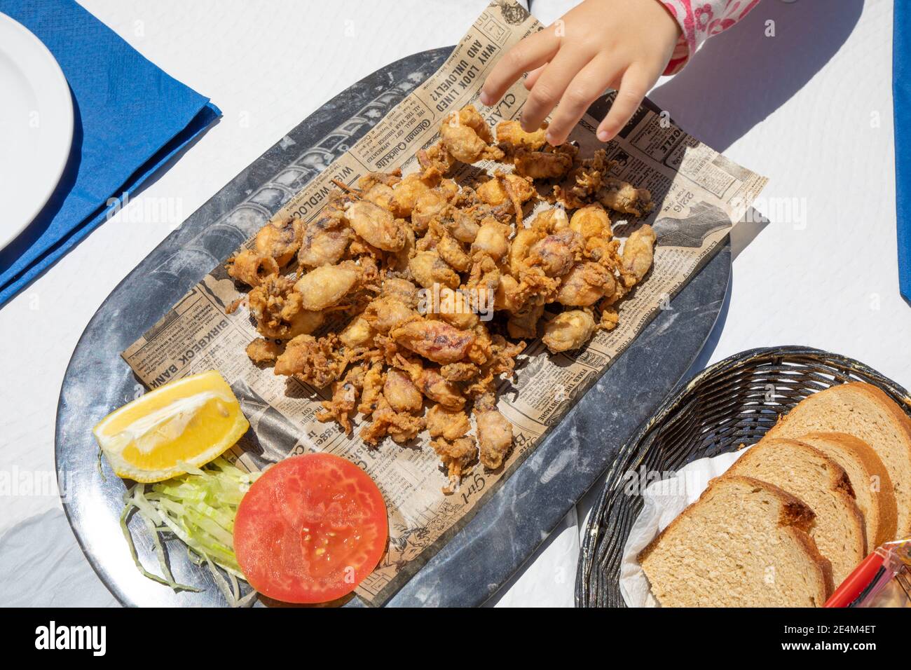aerial view of hand of child taking to eat baby little squids breaded ...
