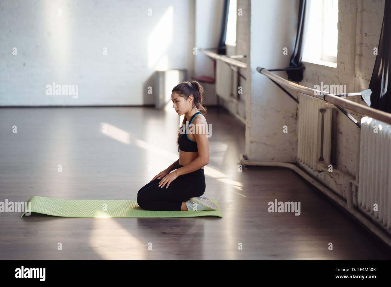 Attractive young woman sitting on mat. Body shape and activity Stock ...
