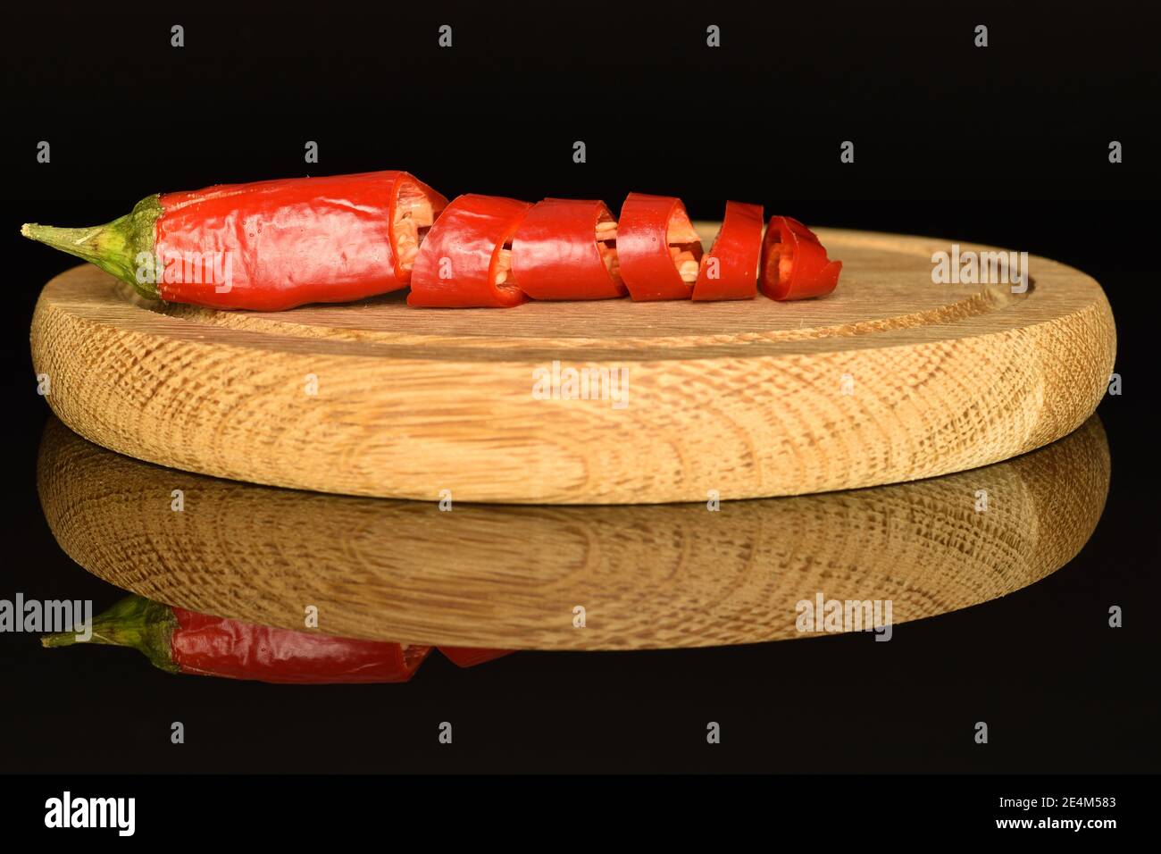 One spicy fragrant red hot pepper cut into several parts, on a black ...