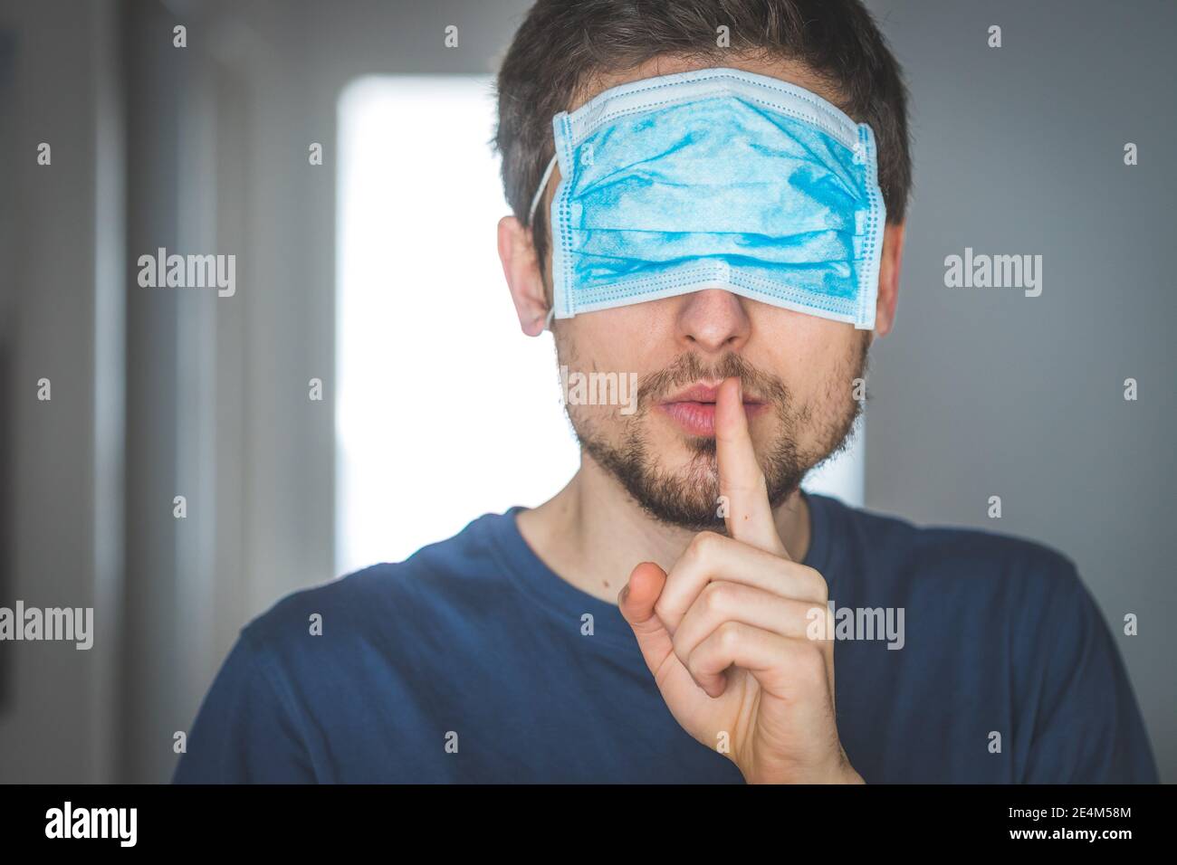 Young angry man with face mask over the eyes is doing a psst! gesture ...