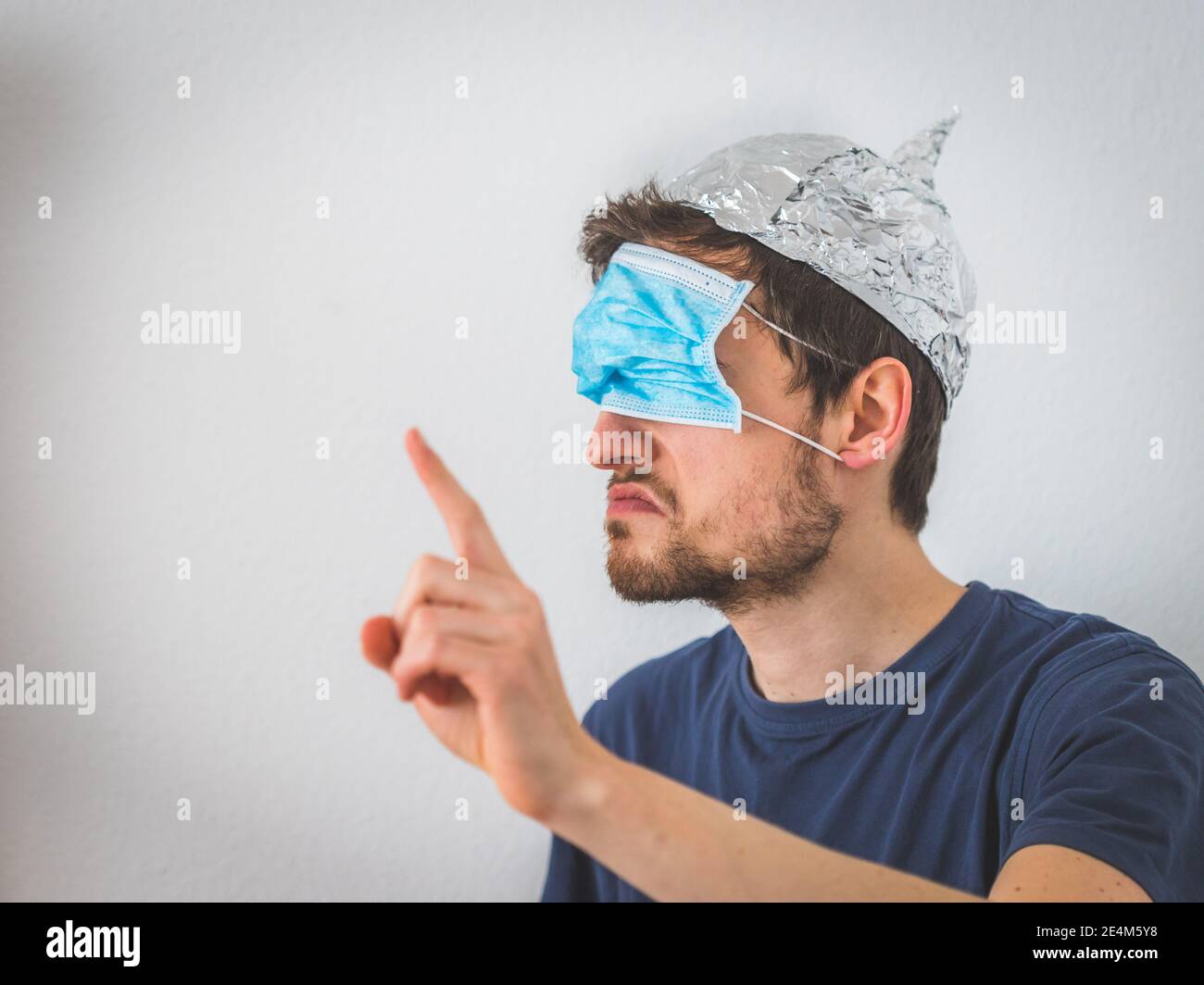 Young angry man with aluminum cap and face mask over the eyes is ...