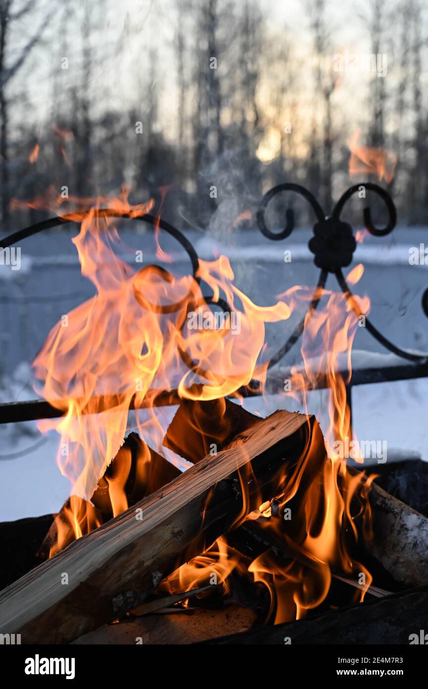 Close-up of burning and smoking wood in wrought iron brazier at winter ...