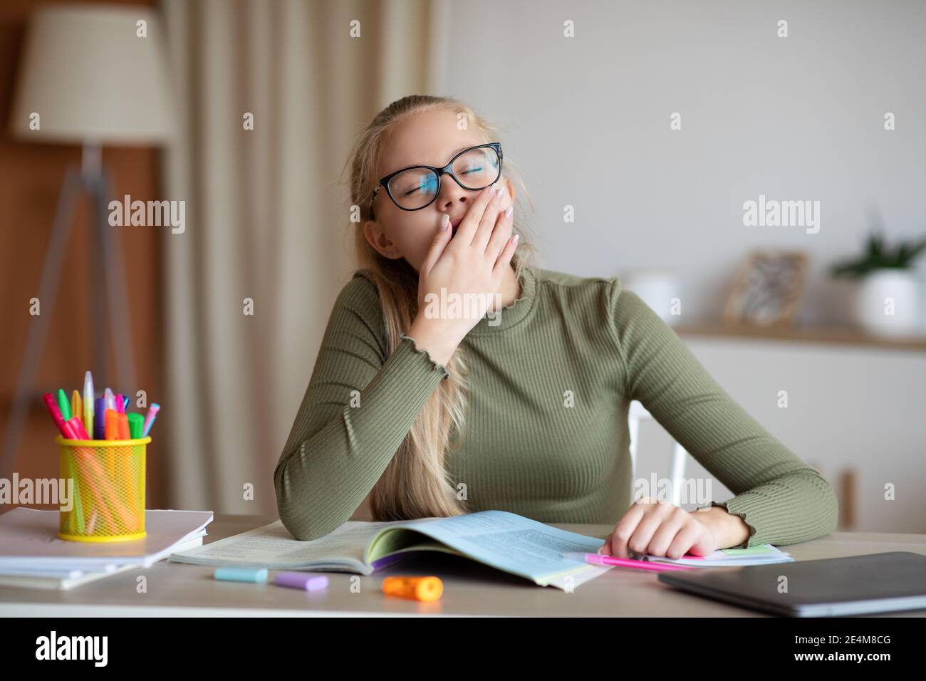 Sleepy teen girl doing homework at home Stock Photo - Alamy