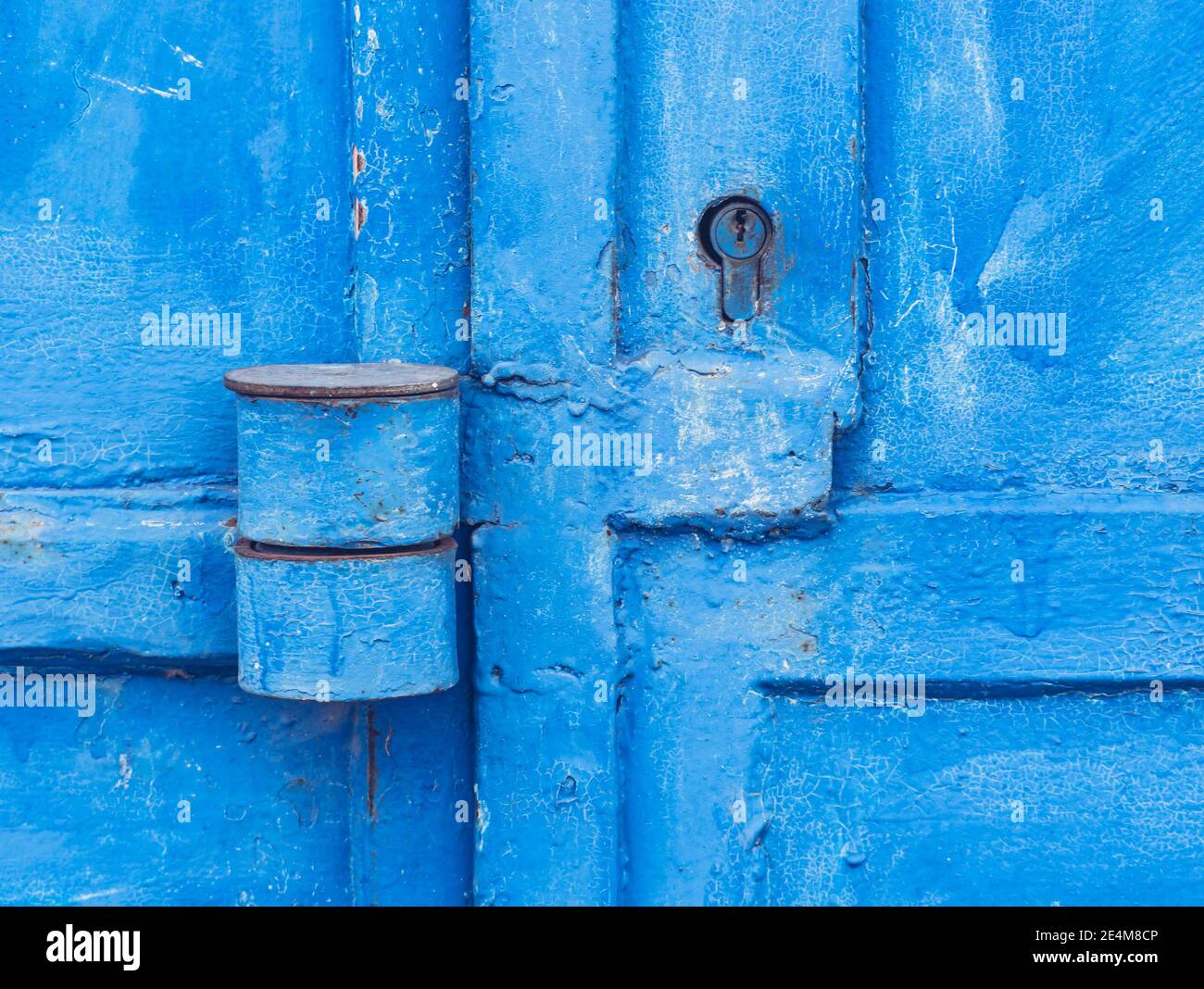 Big metal door with weathered blue paint surface and security insert ...