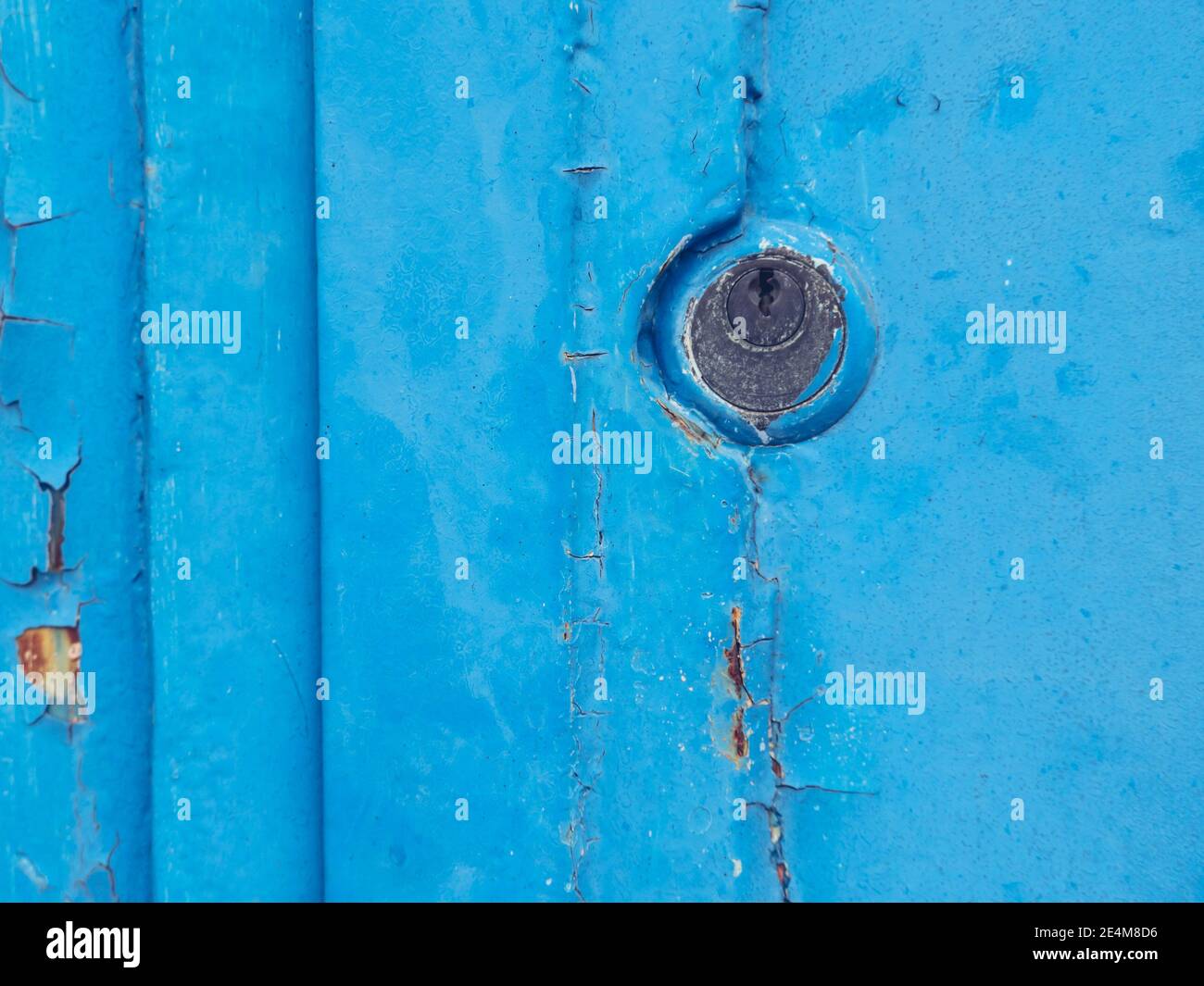Blue metal old keyhole on a worn out metal sheet garage door. Secure ...