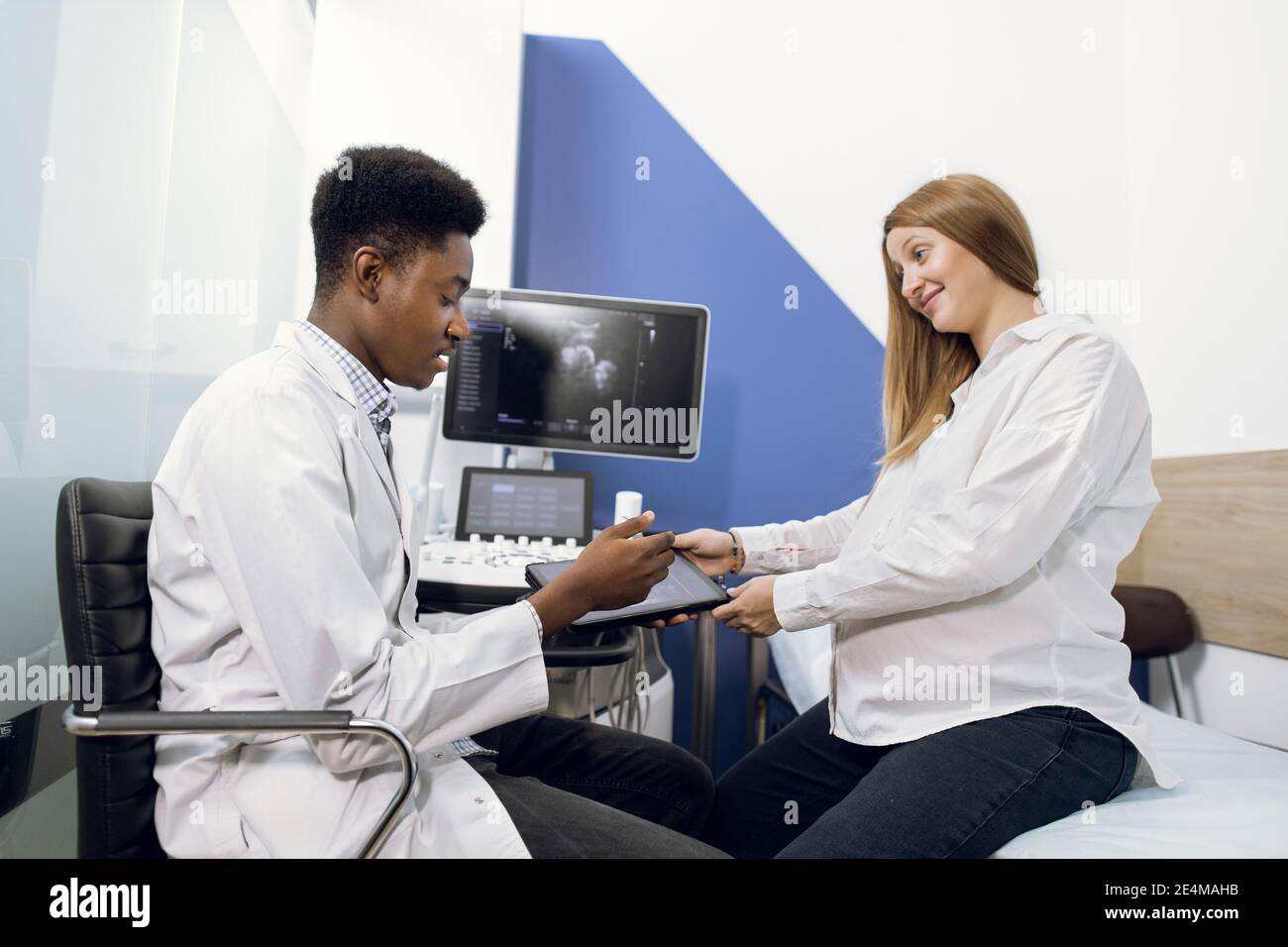 Doctor and patient in ultrasound room. African male doctor talking to ...