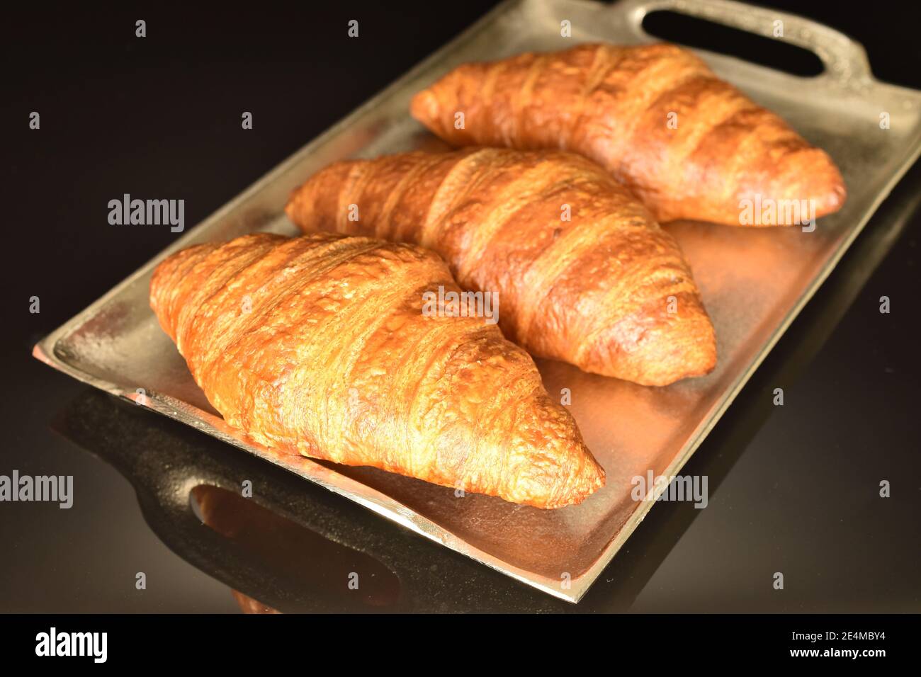 Three whole fragrant sweet fresh crunchy croissants on a black ...