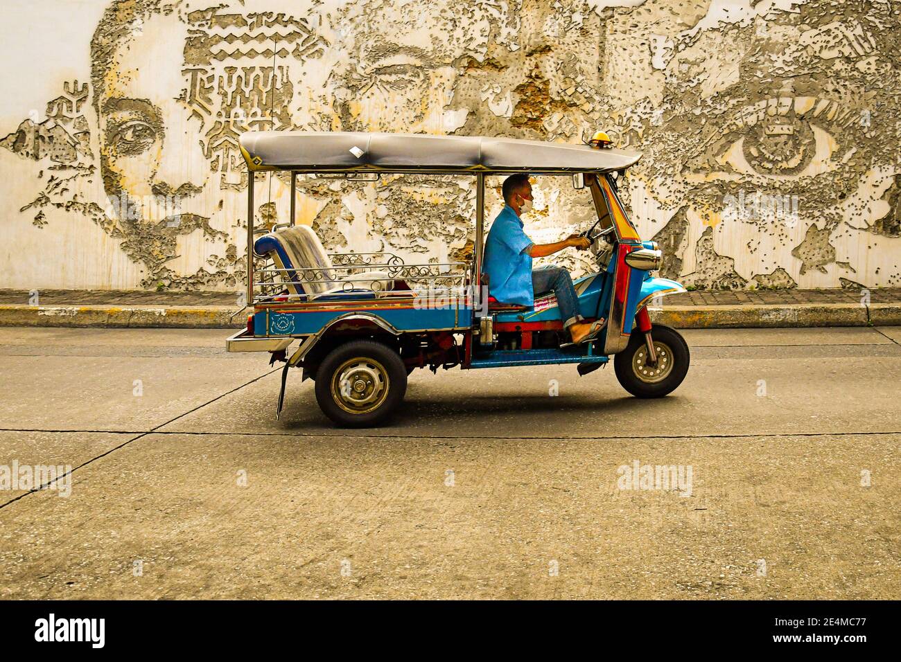A side profile view of a tuk tuk in Bangkok, with the driver wearing a ...