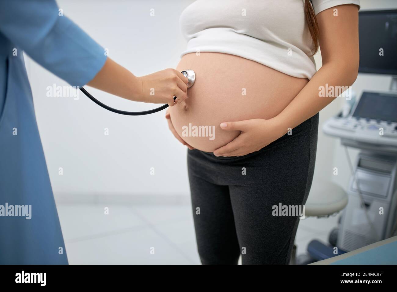 Female doctor measuring pregnant woman's tummy with tape at modern ...
