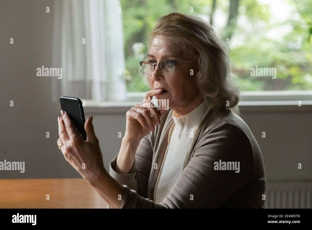 Close up thoughtful upset mature woman looking at phone screen Stock ...