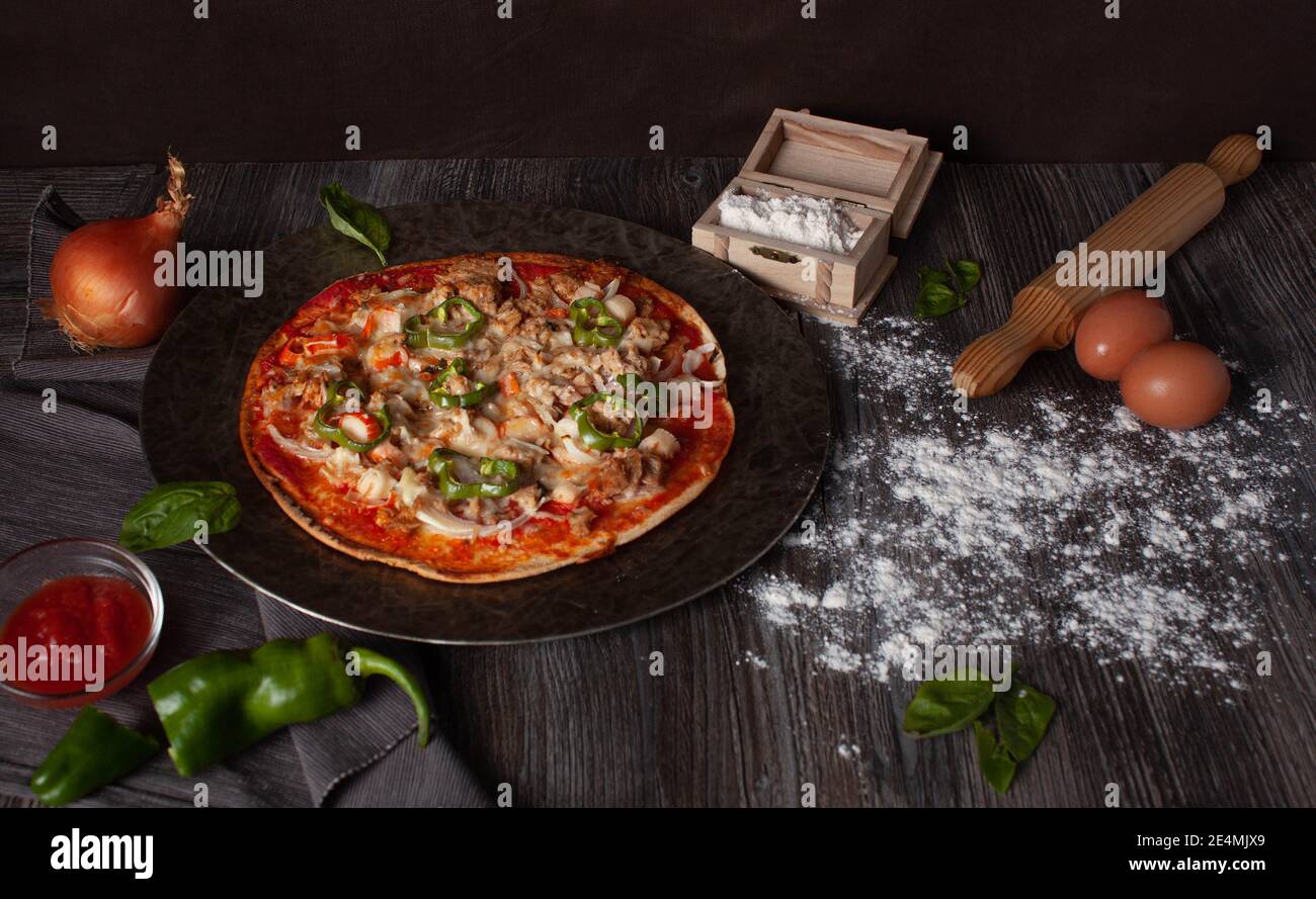 Composition of a table with a pizza with tomato sauce, flour,onion ...