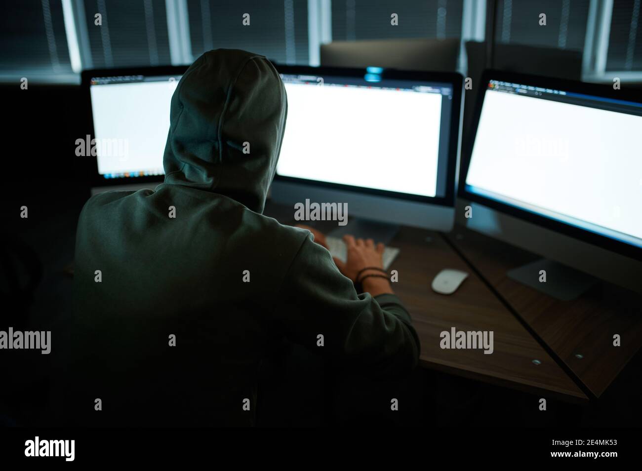 Male internet hacker in hood sitting at monitors Stock Photo - Alamy