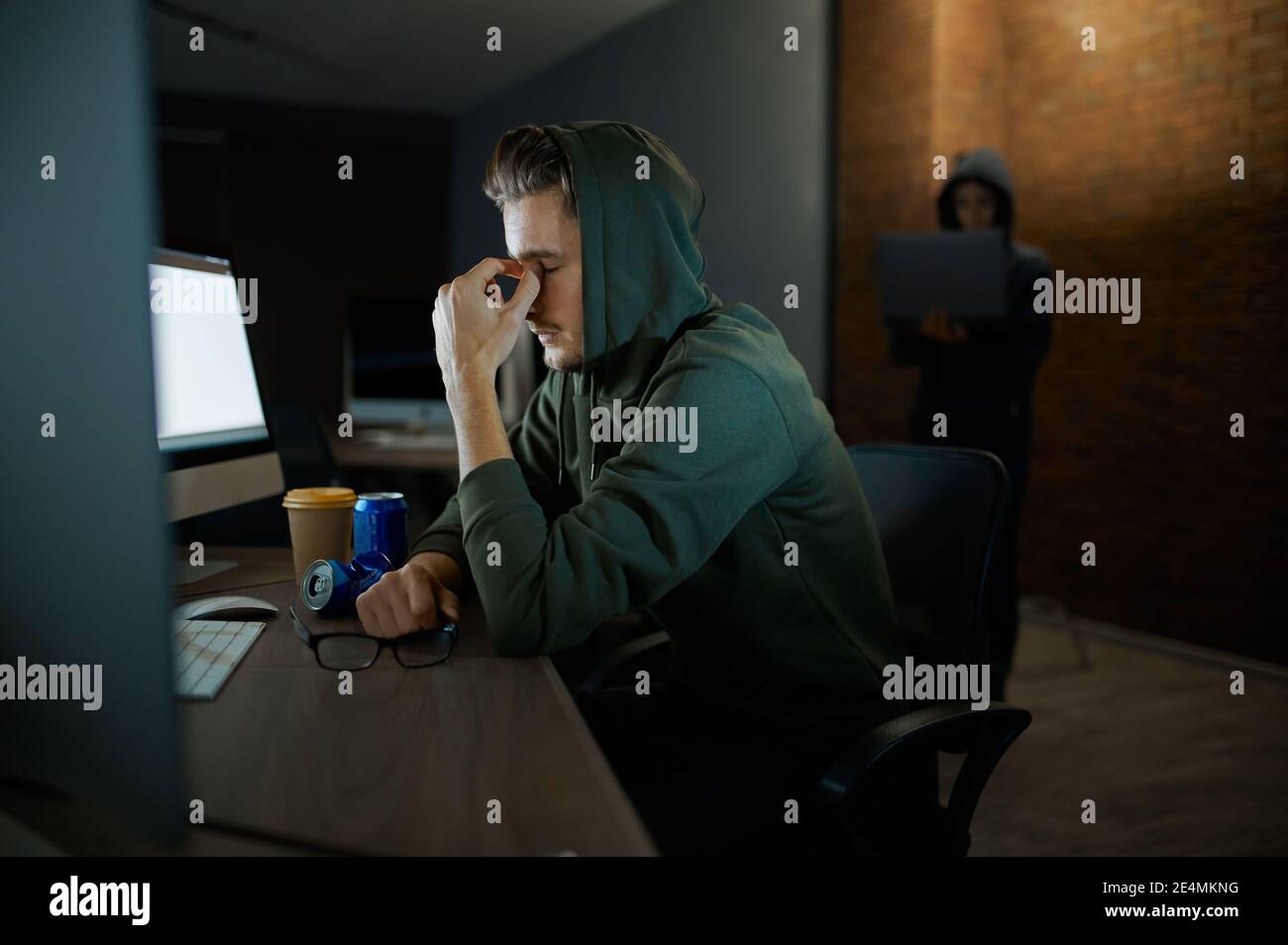 Tired male hacker in hood sitting at monitors Stock Photo - Alamy