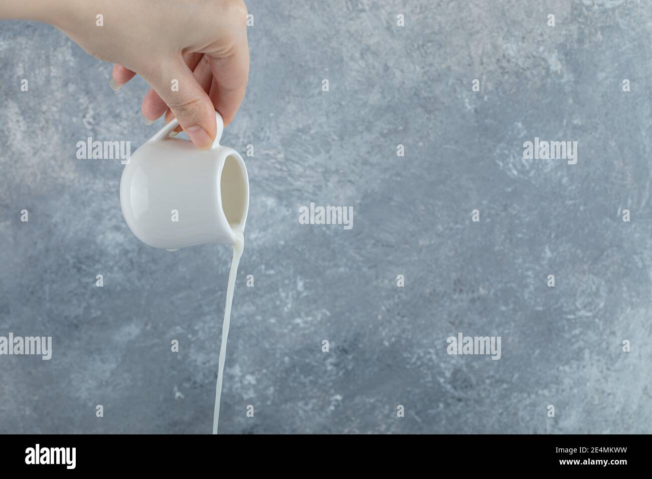 Female hand pouring fresh milk out of small mug Stock Photo - Alamy
