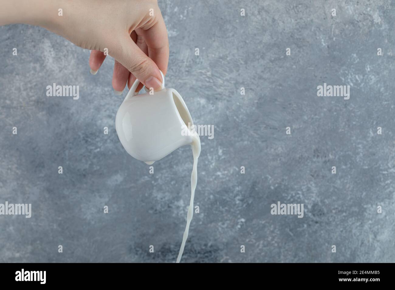 Female hand pouring fresh milk out of small mug Stock Photo - Alamy