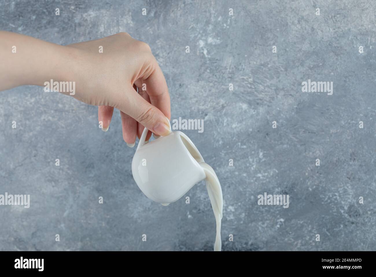 Female hand pouring fresh milk out of small mug Stock Photo - Alamy