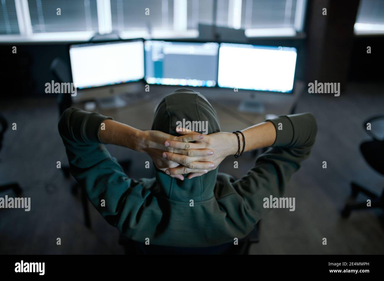 Male hacker in hood sitting at screens, back view Stock Photo - Alamy