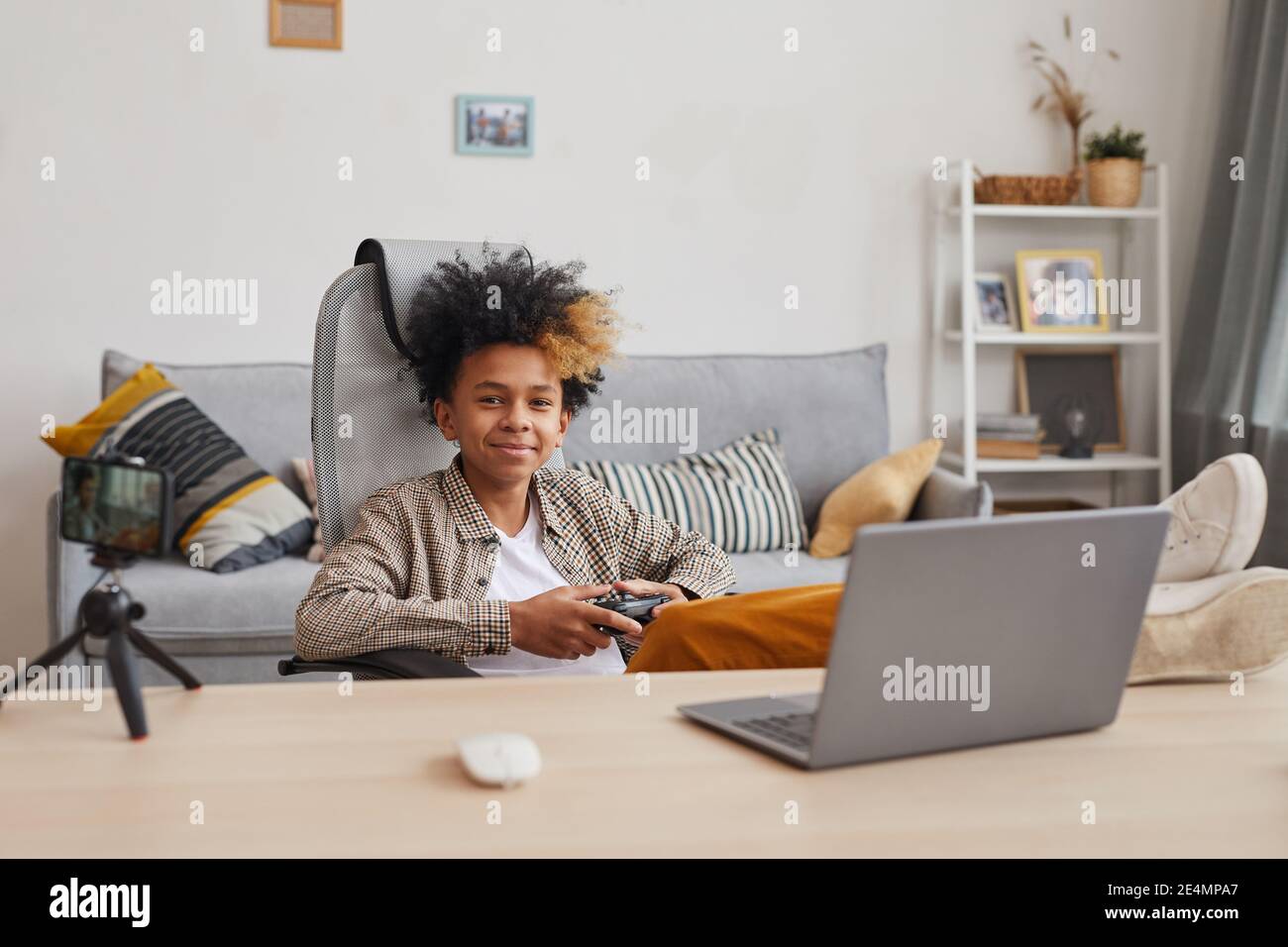 Portrait of smiling African-American boy playing video games at home ...
