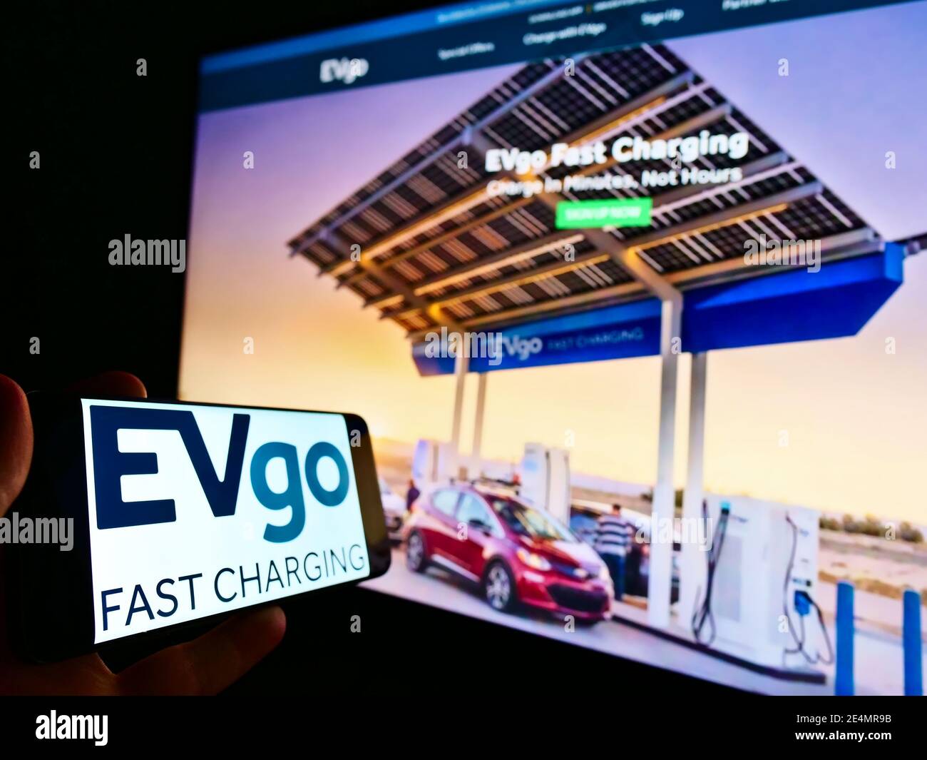 Holding mobile phone with logo of EVgo Services LLC, a provider of ...