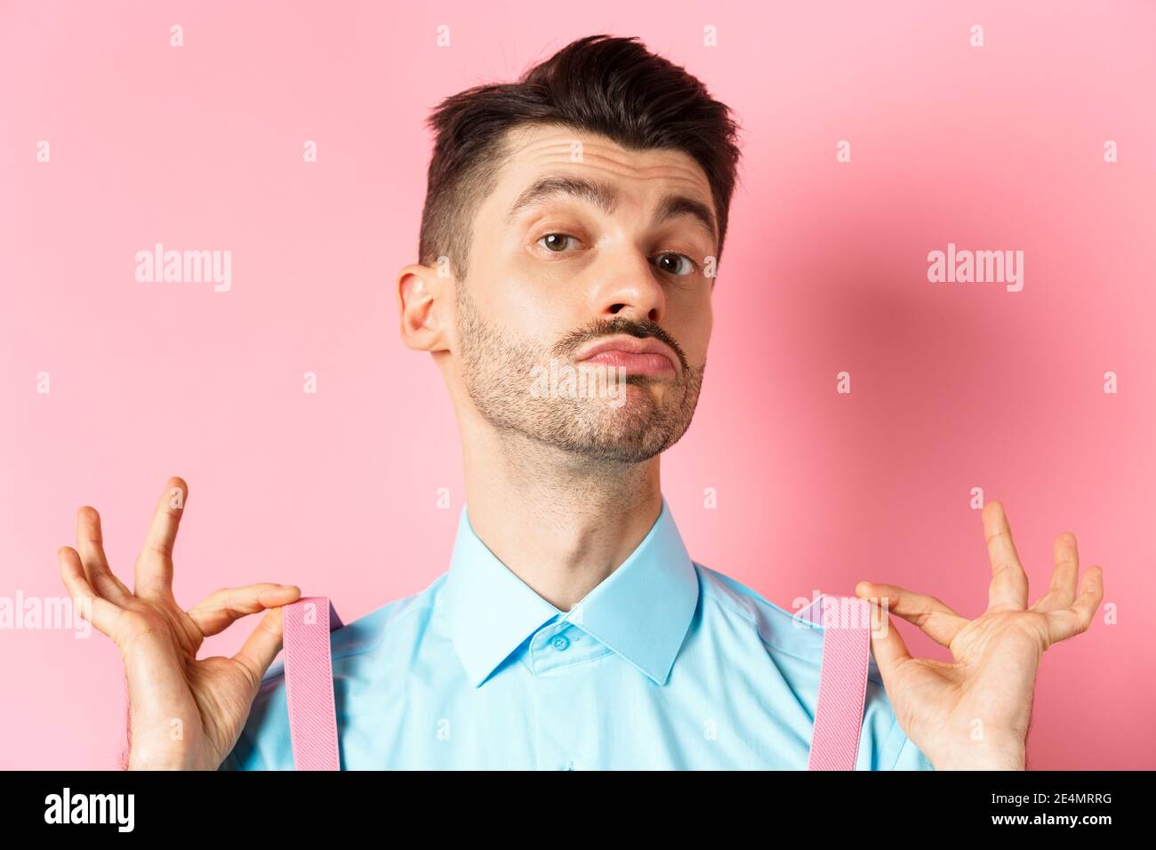Close up of classy handsome guy adjusting suspenders, pucker lips and ...