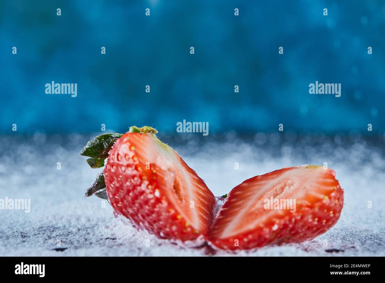 Fresh strawberry slices on blue background with powder Stock Photo - Alamy