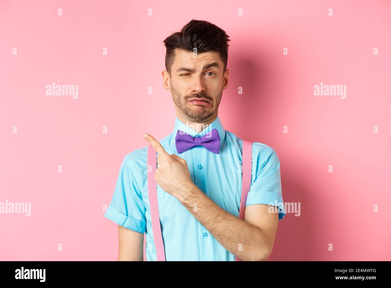 Childish young man acting sad and fake crying while pointing finger ...