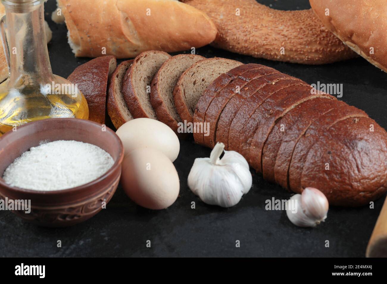 Whole and sliced bread, eggs, garlic, flour bowl and glass of oil Stock ...