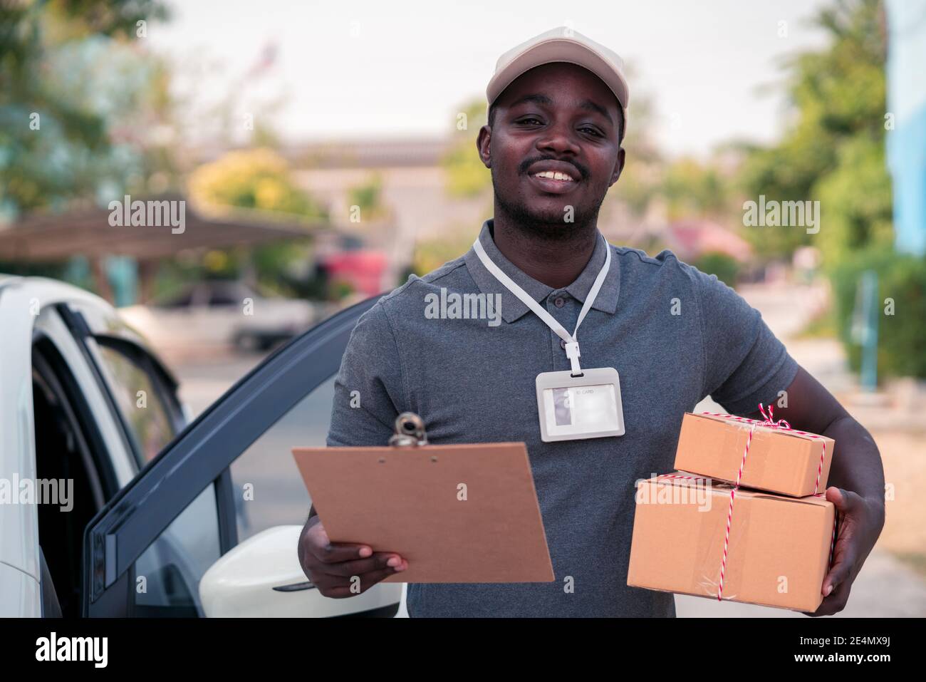African male postal delivery courier man holding delivering package ...