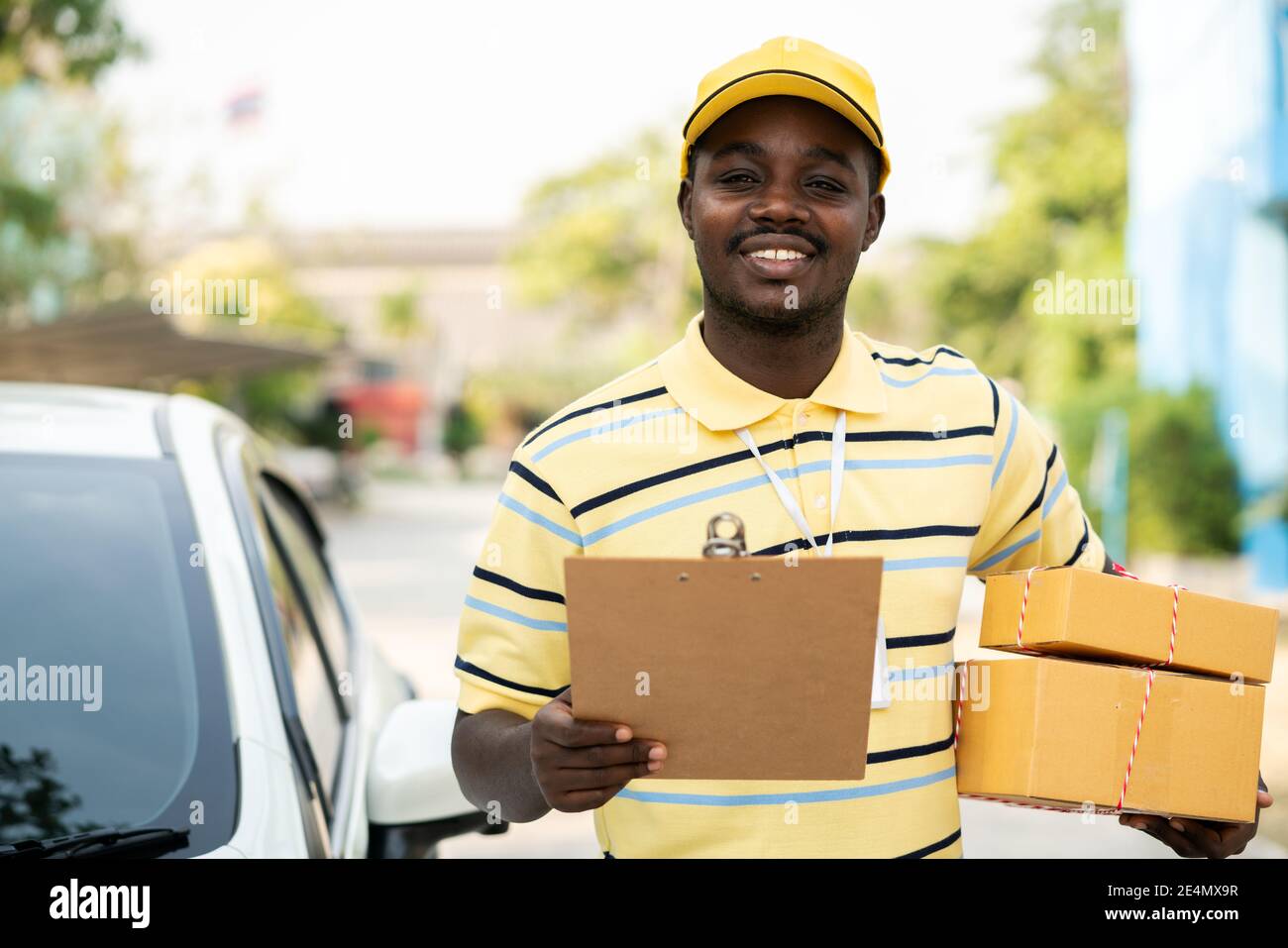 African male postal delivery courier man holding delivering package ...