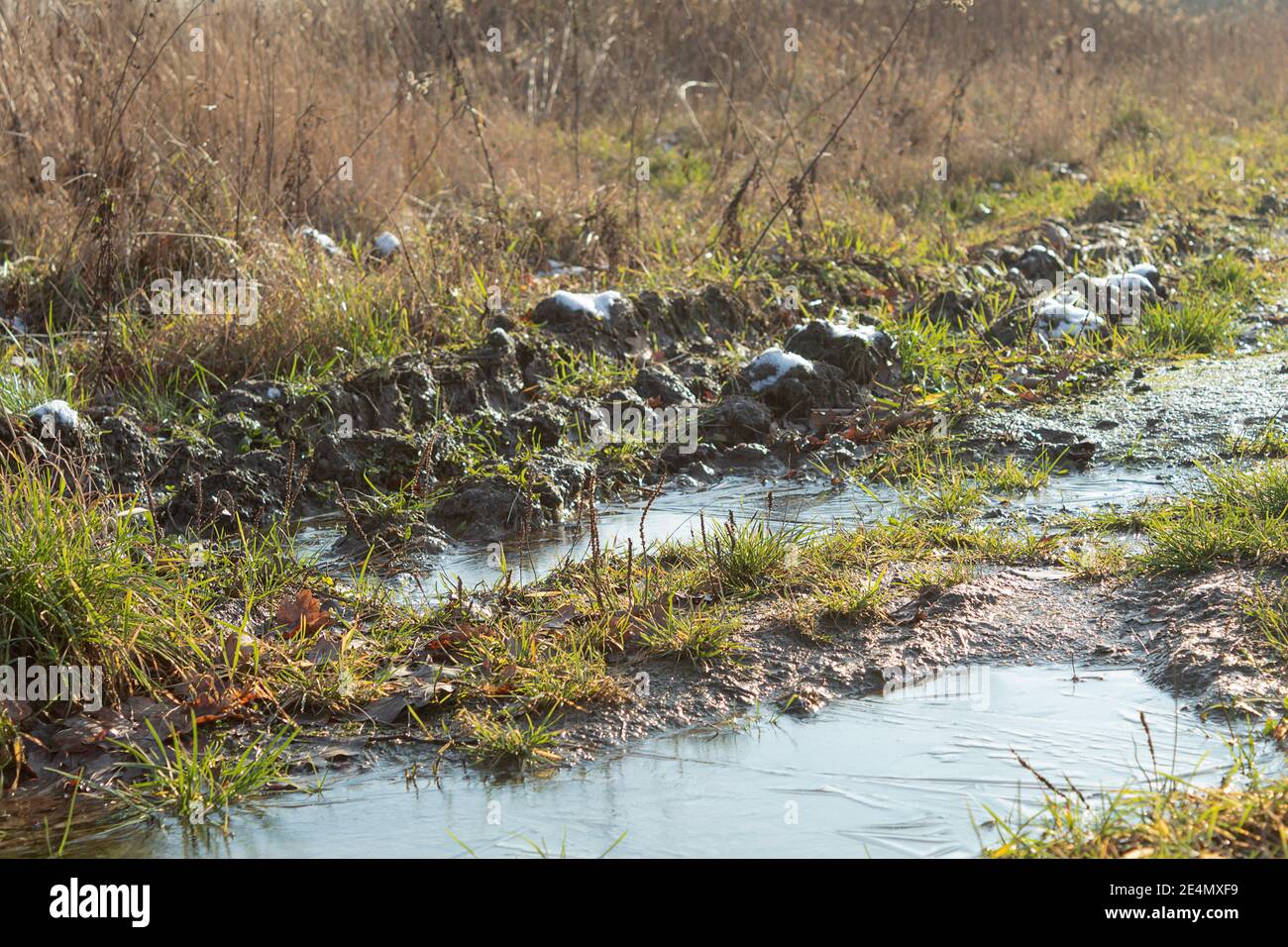First snow and frost on a dirt road. Frozen dirt road and mud with snow ...