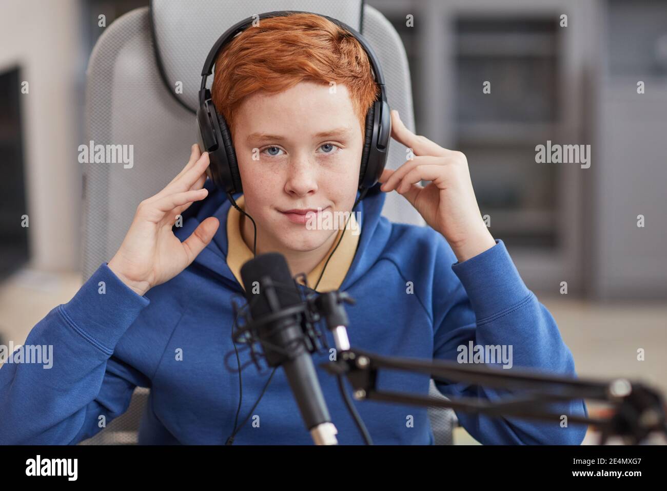 Front view portrait of red haired teenage boy speaking to microphone ...