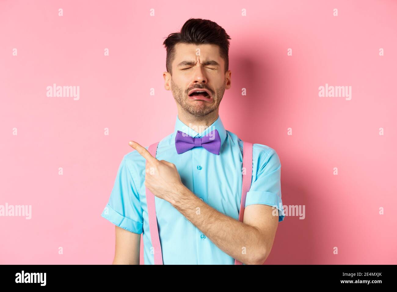 Sad and lonely man in bow-tie crying and pointing finger left, feeling ...