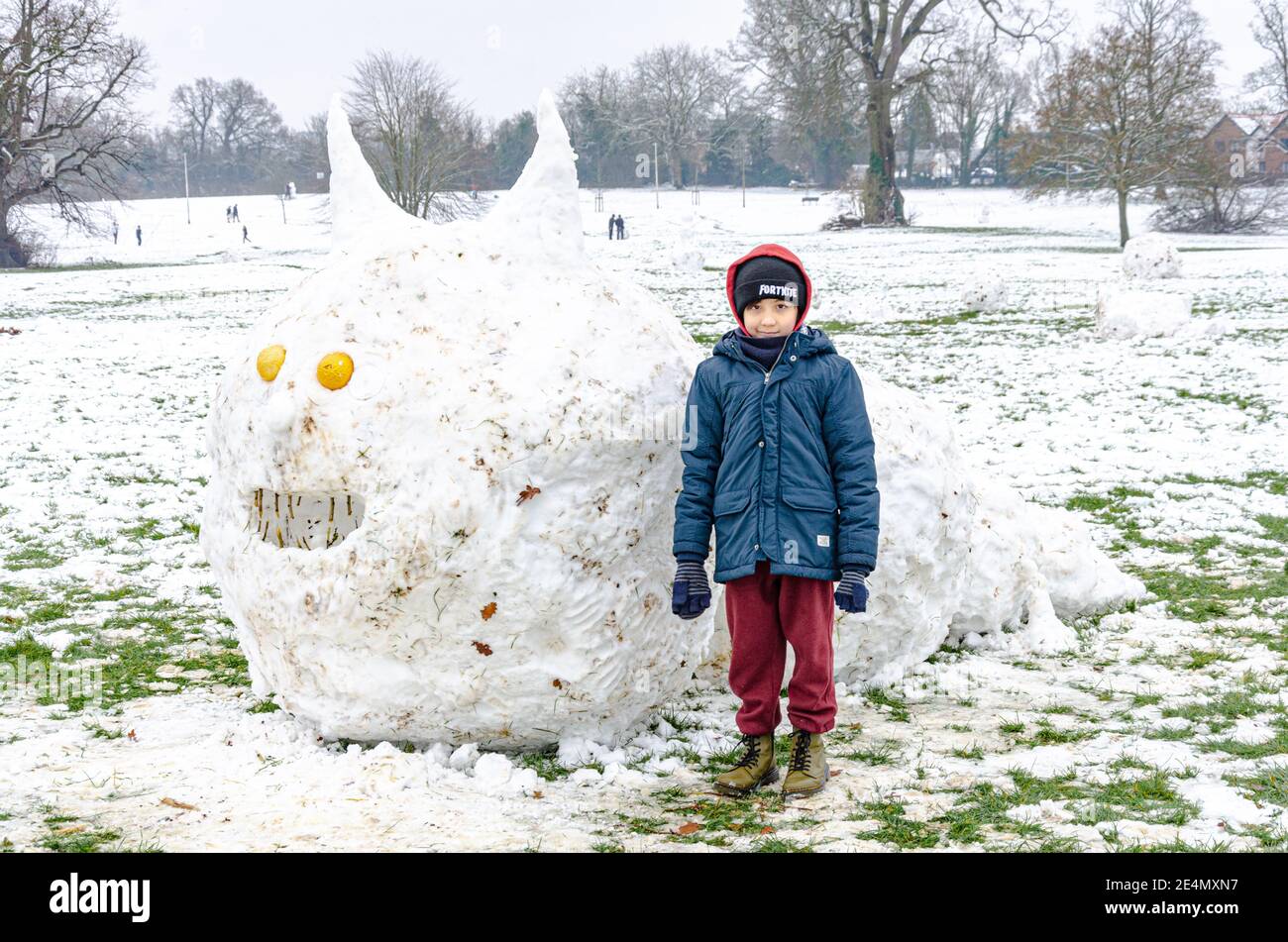 A young boy stands next to a caterpillar like creature sculpted out of ...