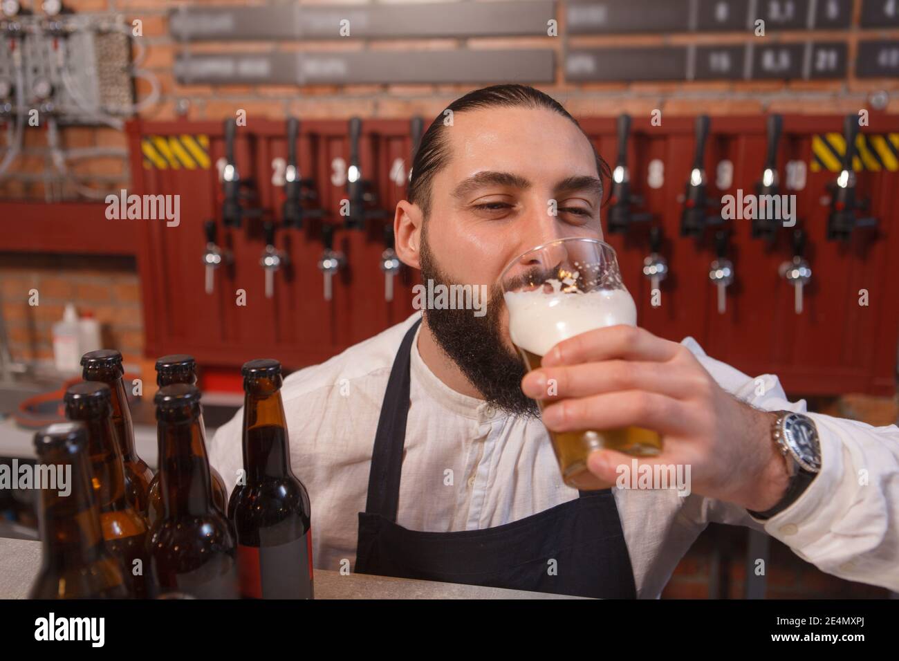 Bartender sipping delicious beer, closing eyes in pleasure Stock Photo ...