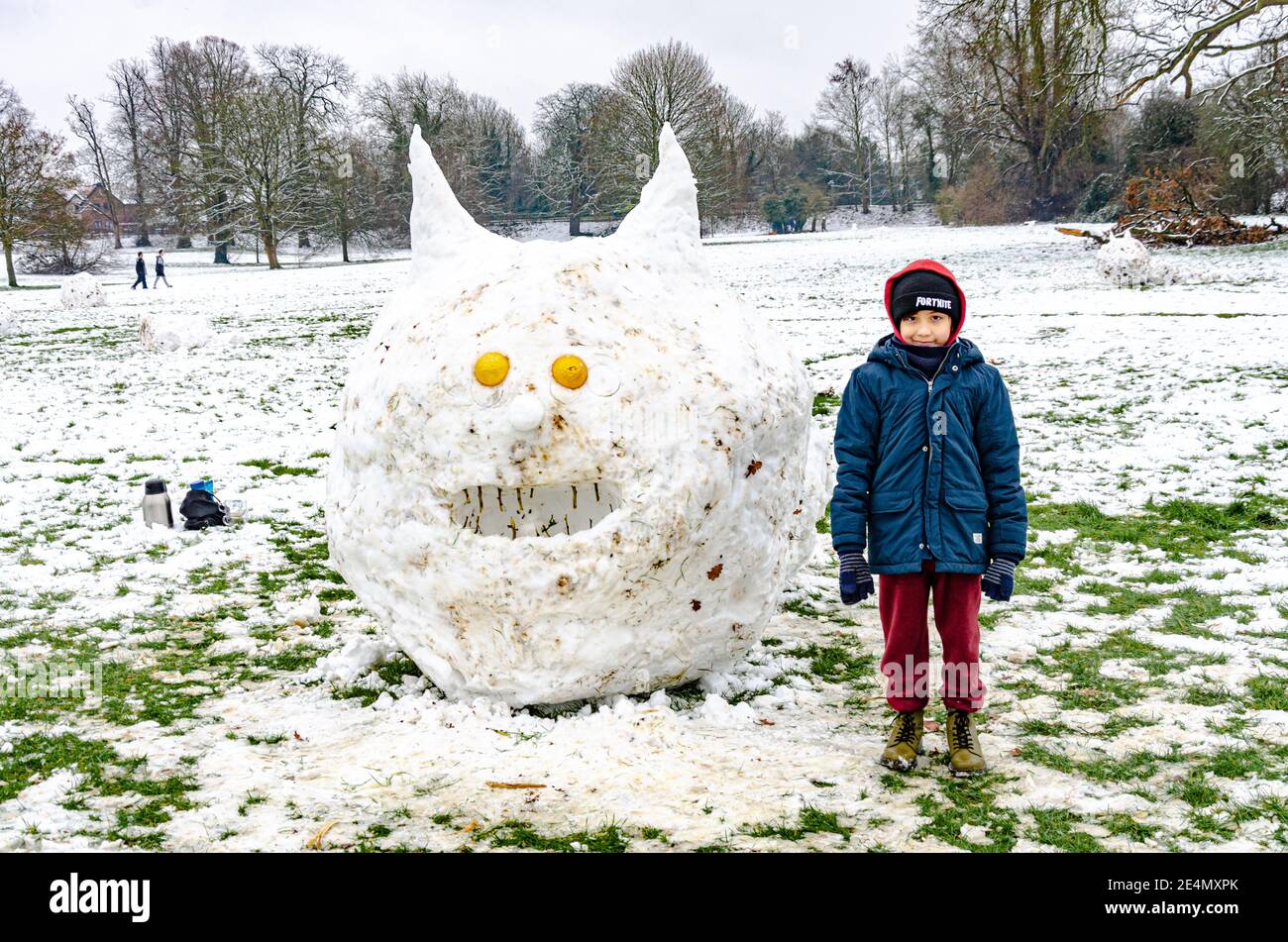 A young boy stands next to a caterpillar like creature sculpted out of ...