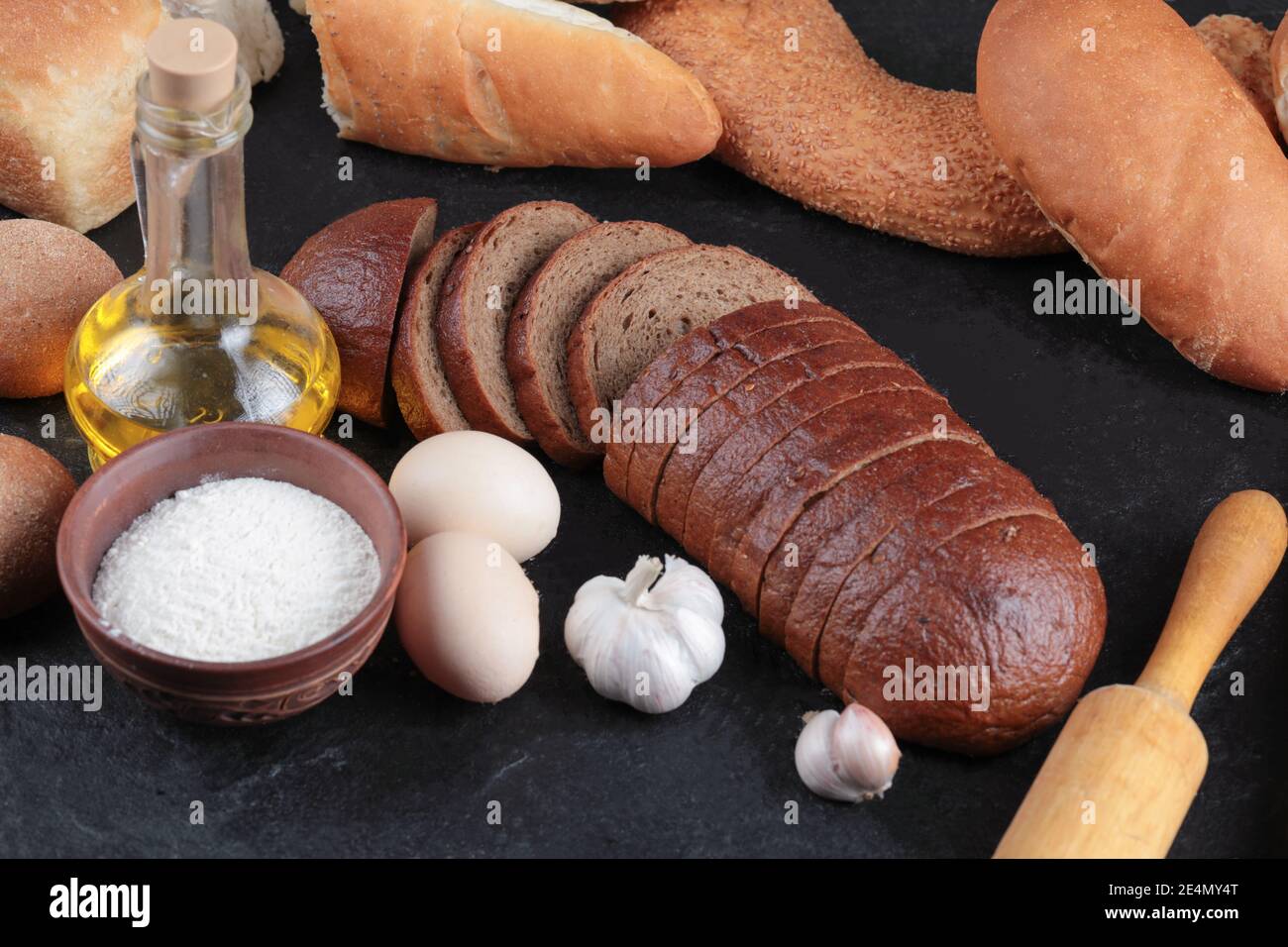 Whole and sliced bread, eggs, garlic, flour bowl and glass of oil Stock ...