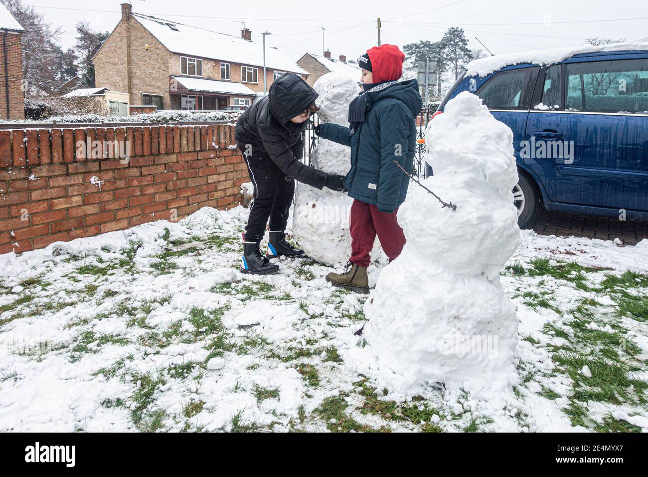 Children building a snowman out of snow in a front garden in Reading ...