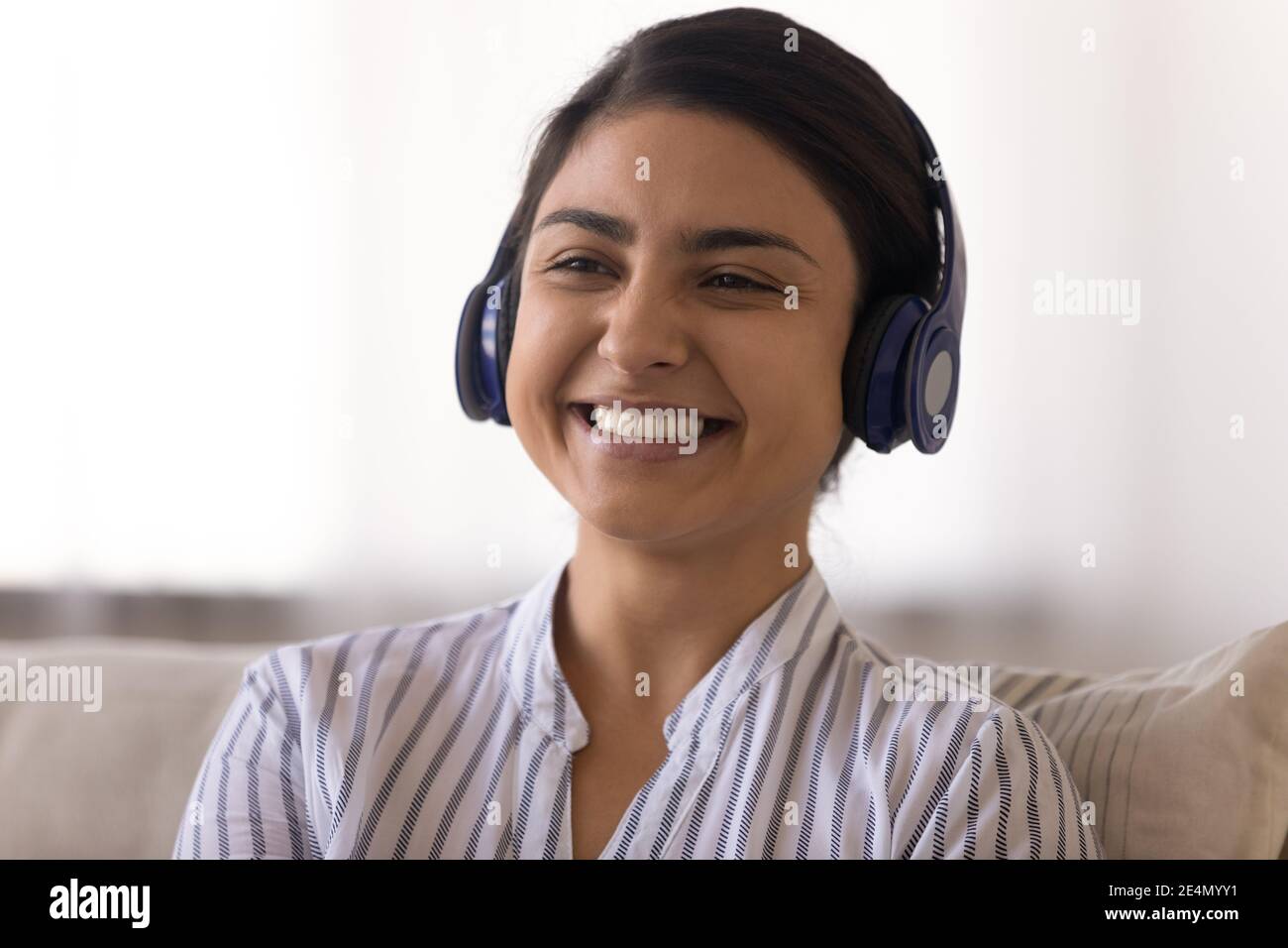 Positive young hindu lady in headset listening to audio book Stock ...